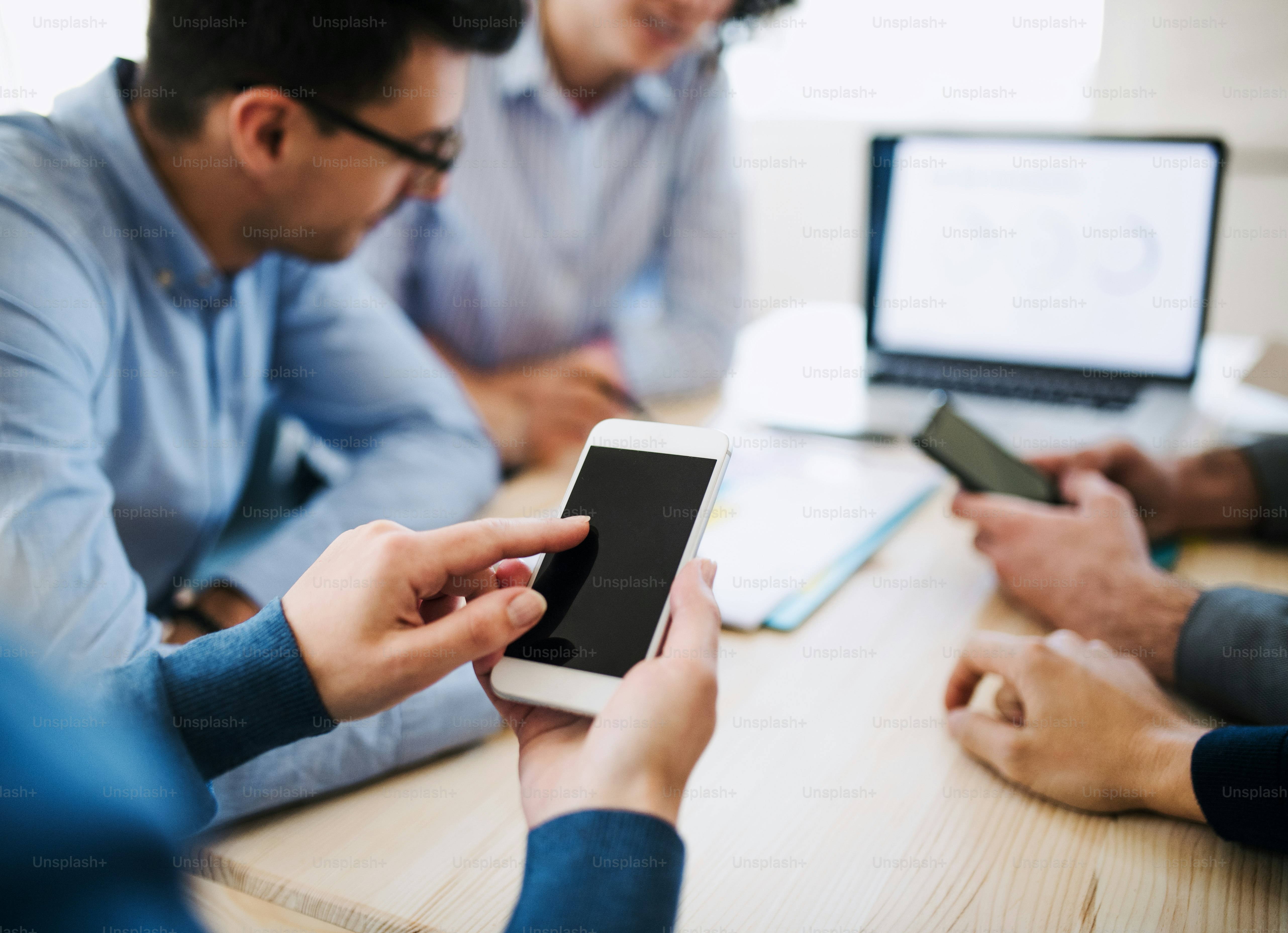 A midsection of group of young businesspeople with smartphone having ...