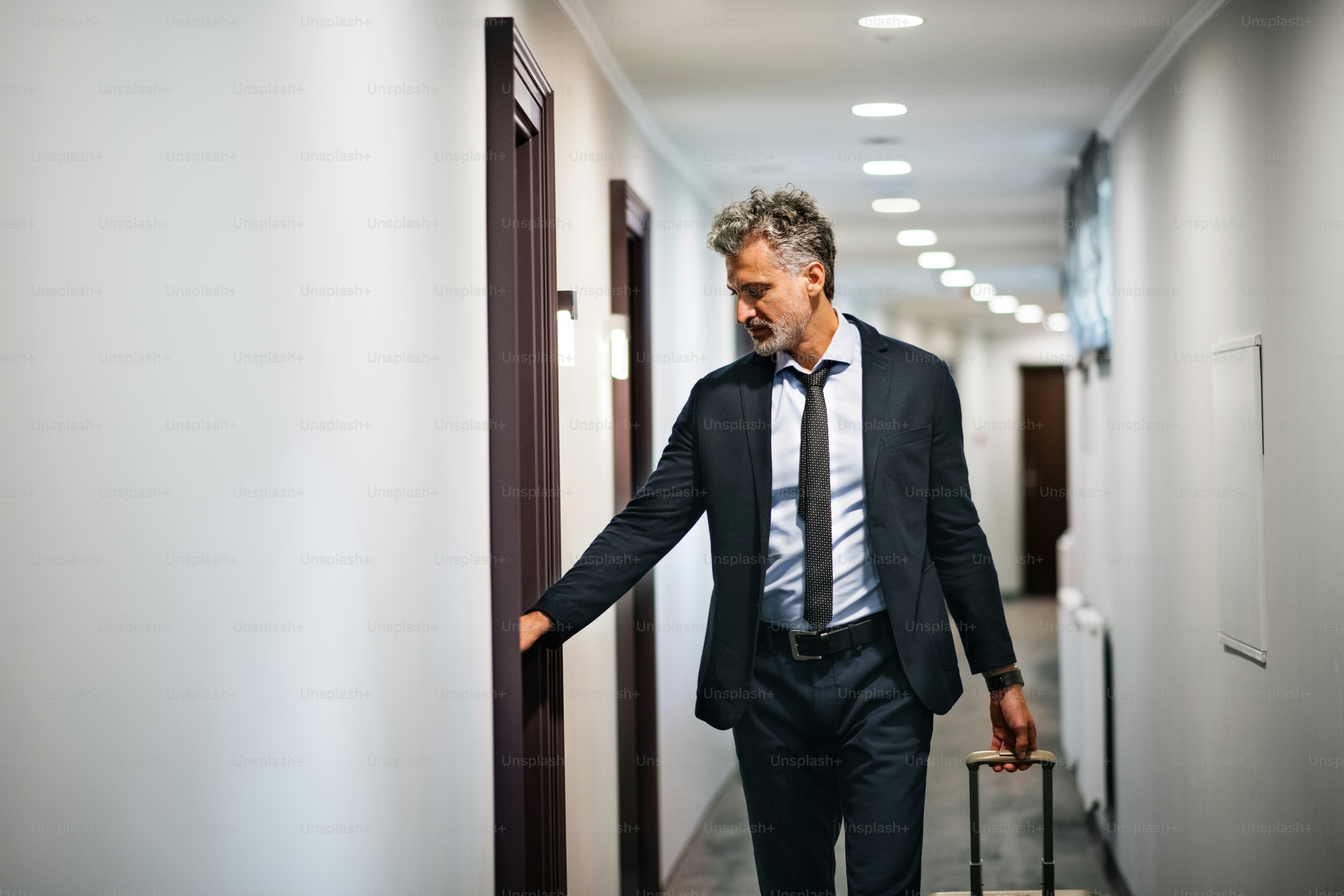 Mature businessman standing at the big windows in a hotel. Man looking ...