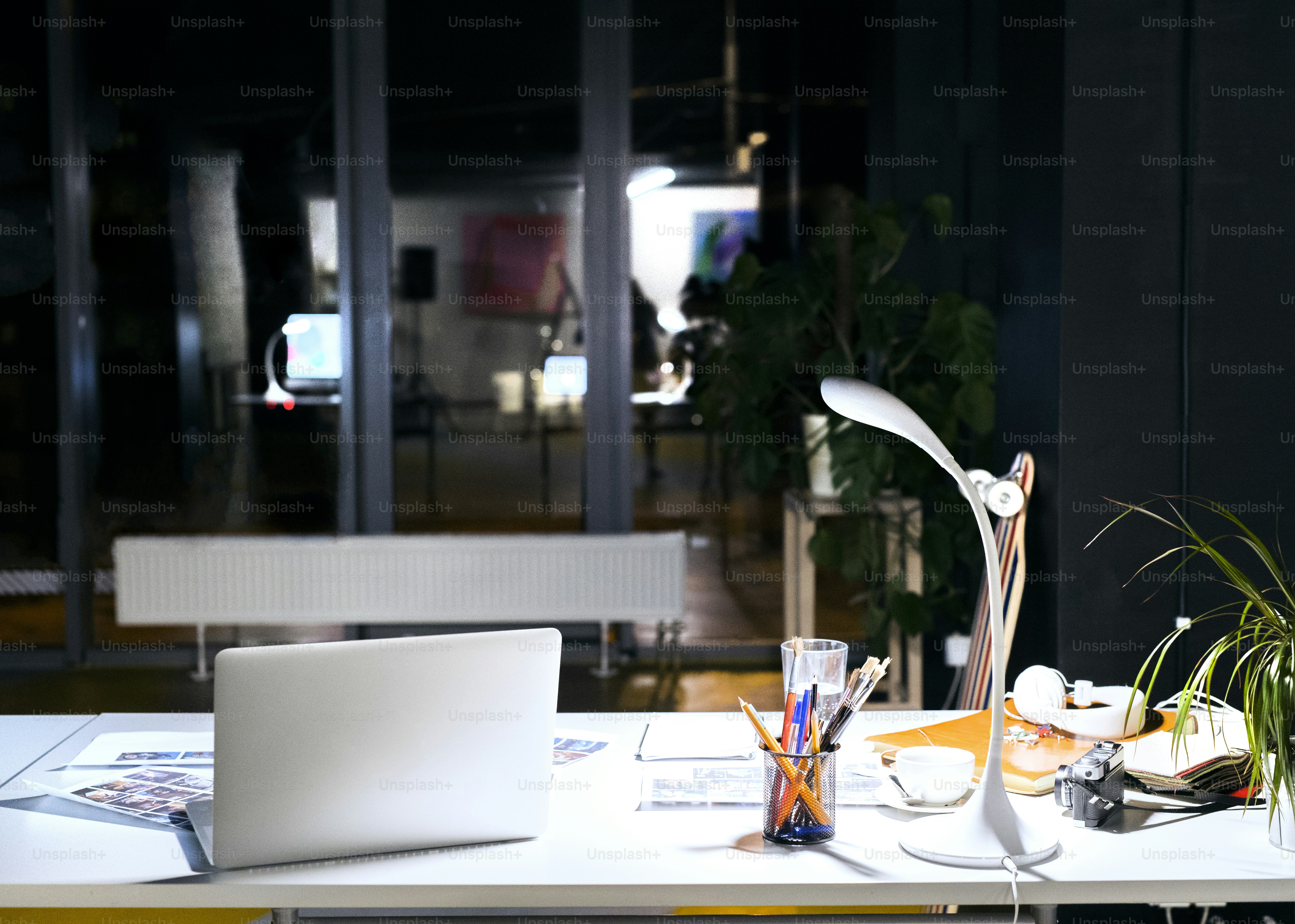 Office desk late at night with laptop, lamp and other things. photo ...
