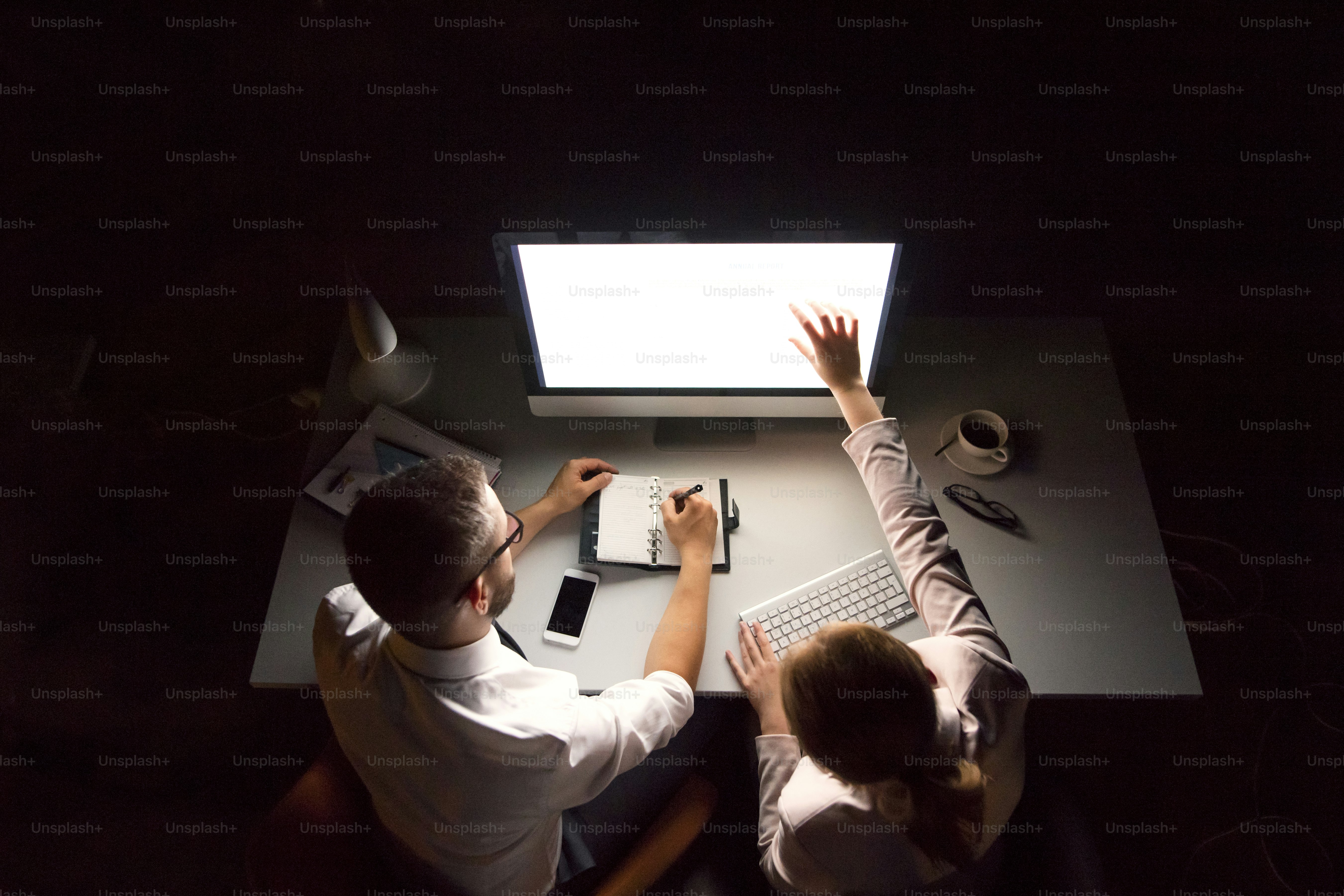 Two young businesspeople in the office at night working late ...
