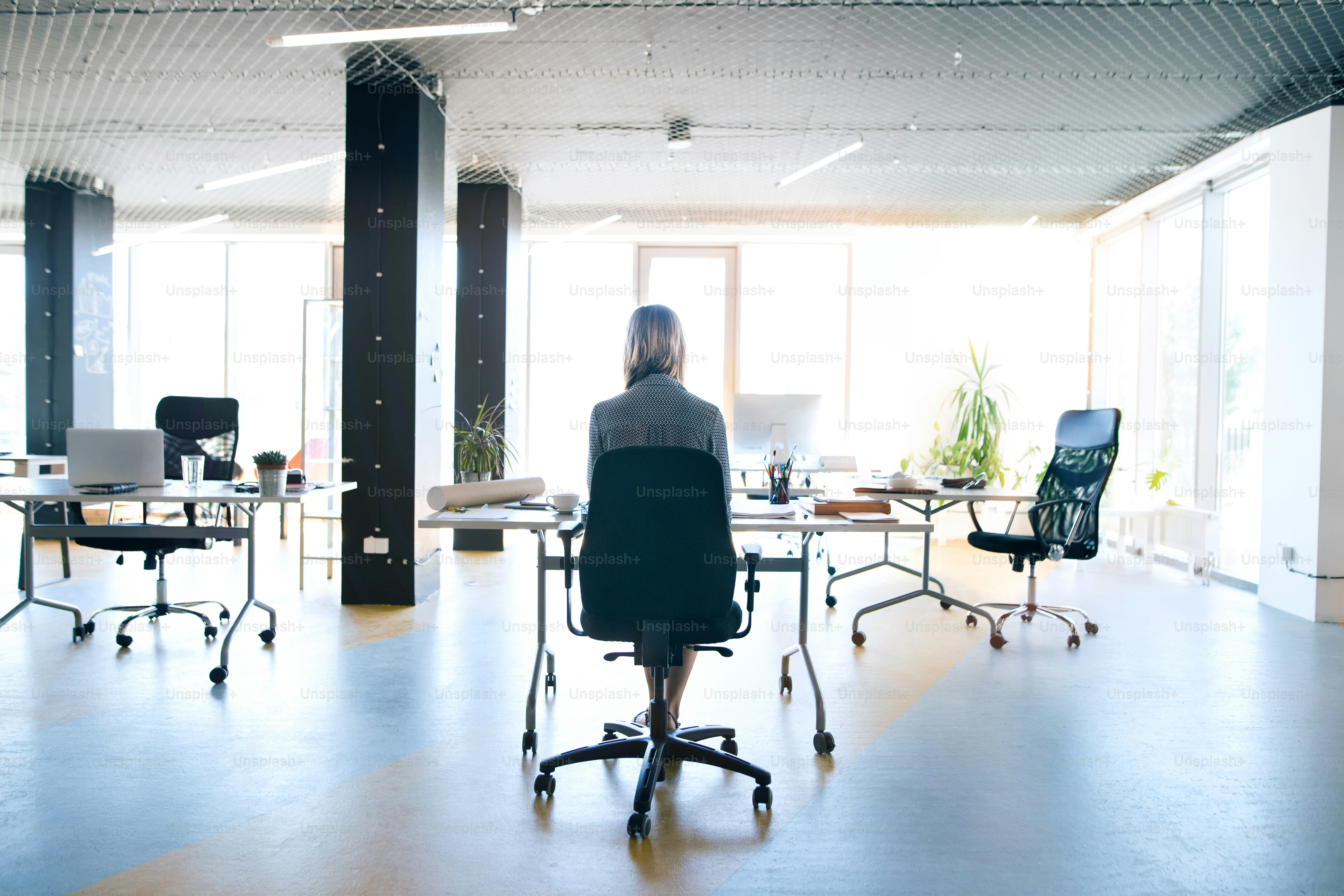 Beautiful young businesswoman in her office, sitting at the desk ...