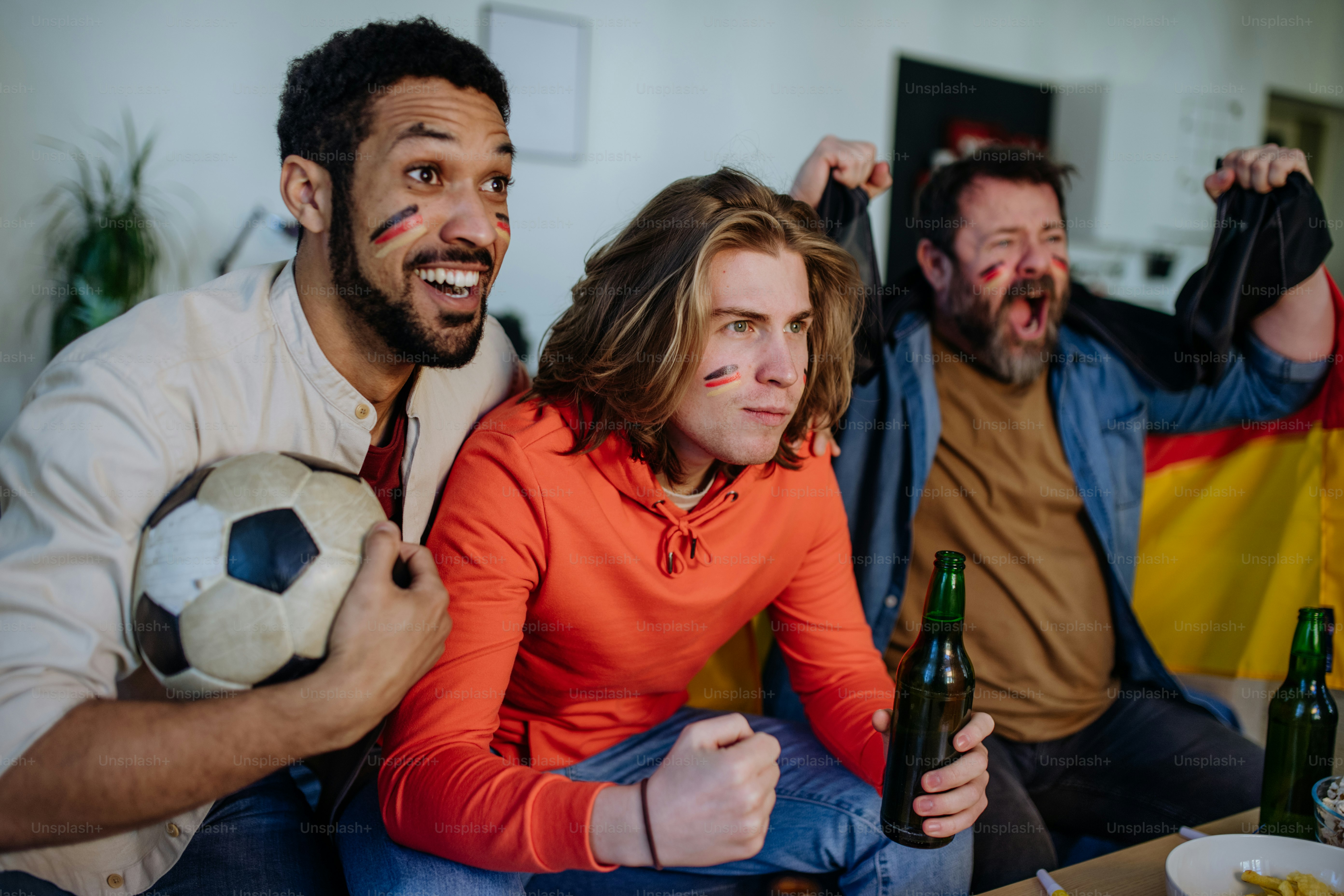 Happy German football fans friends watching football at home and ...