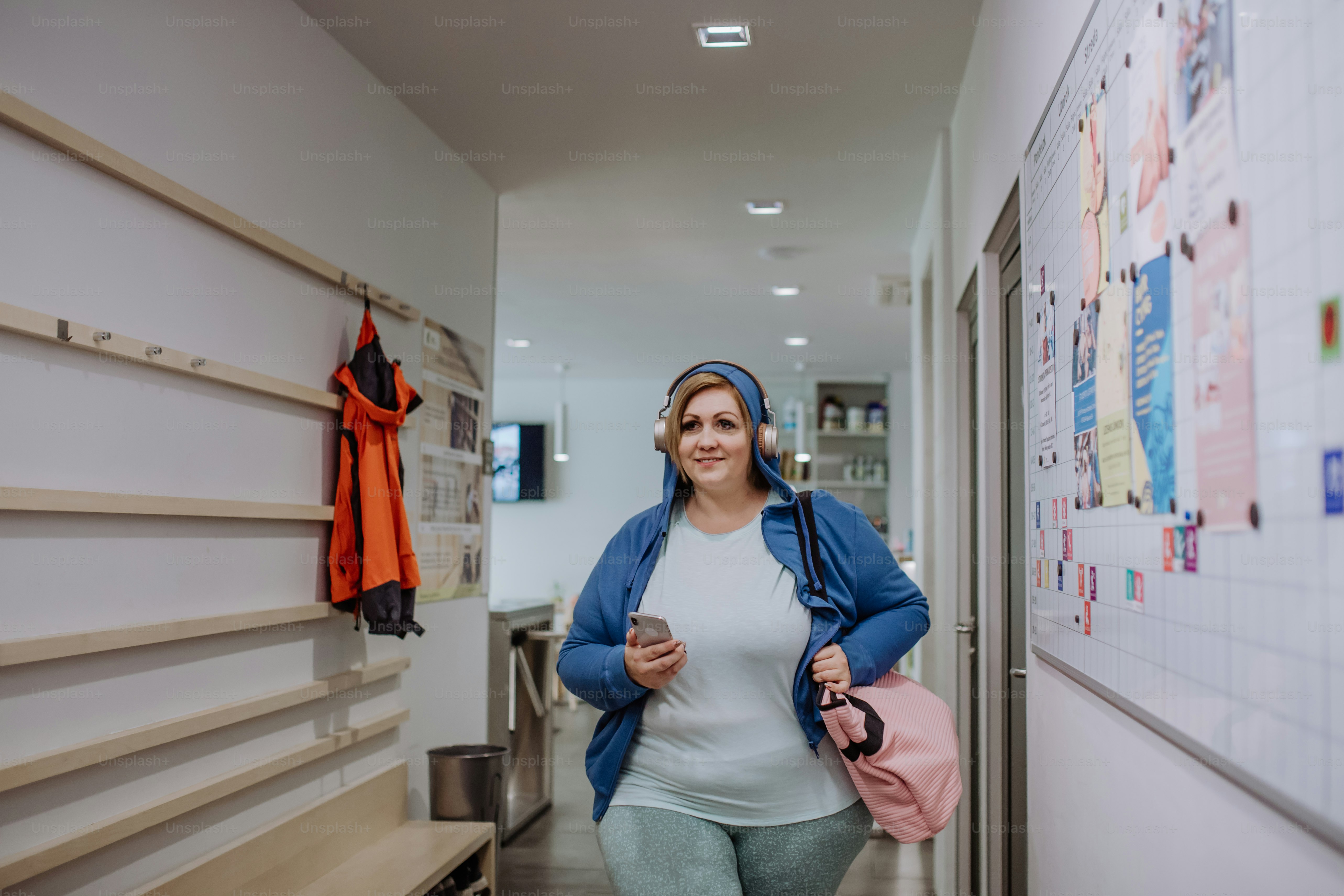 A happy overweight woman in sports clothes indoors in corridor on the ...
