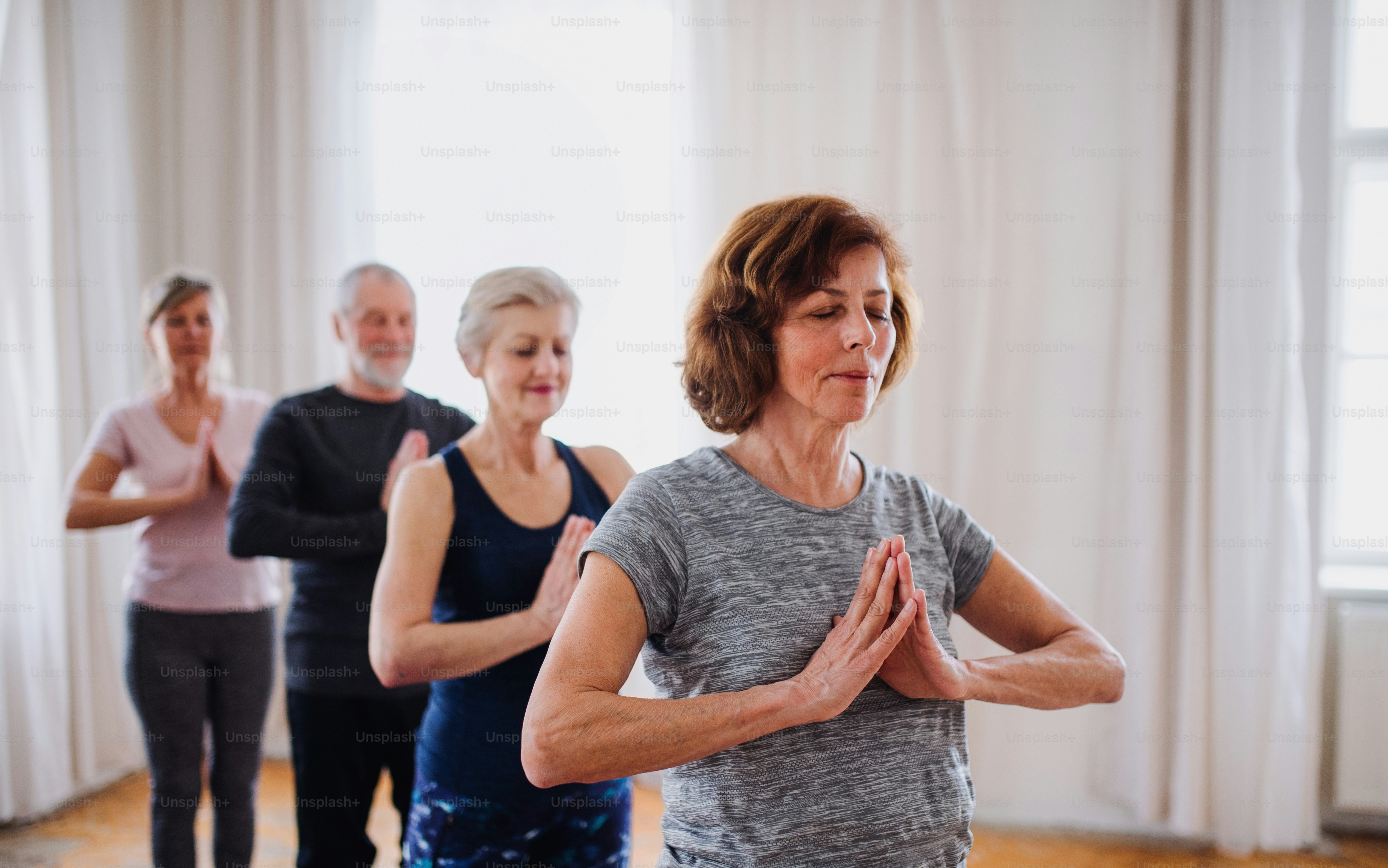 Group of active senior people doing yoga exercise in community center ...