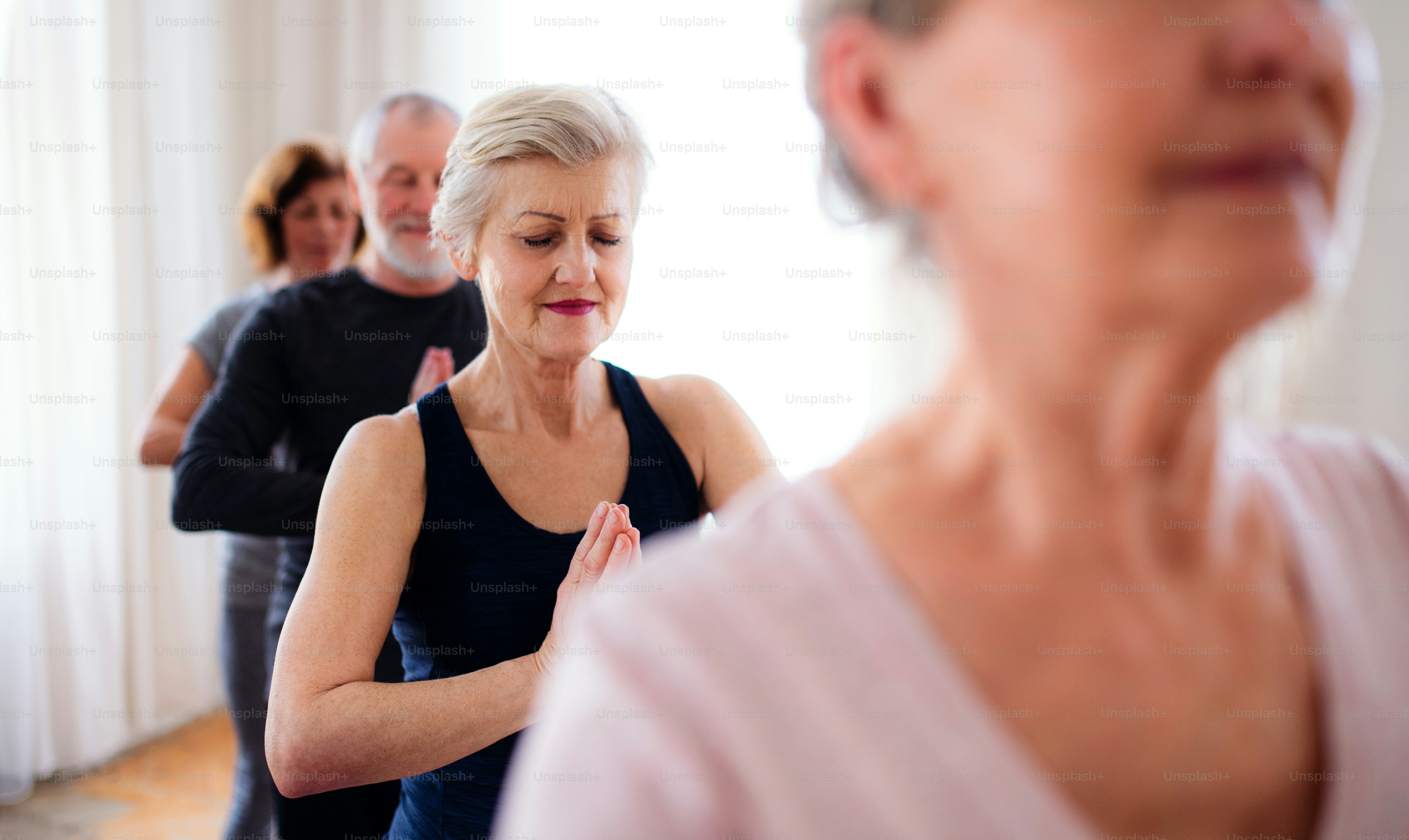Group of active senior people doing yoga exercise in community center ...