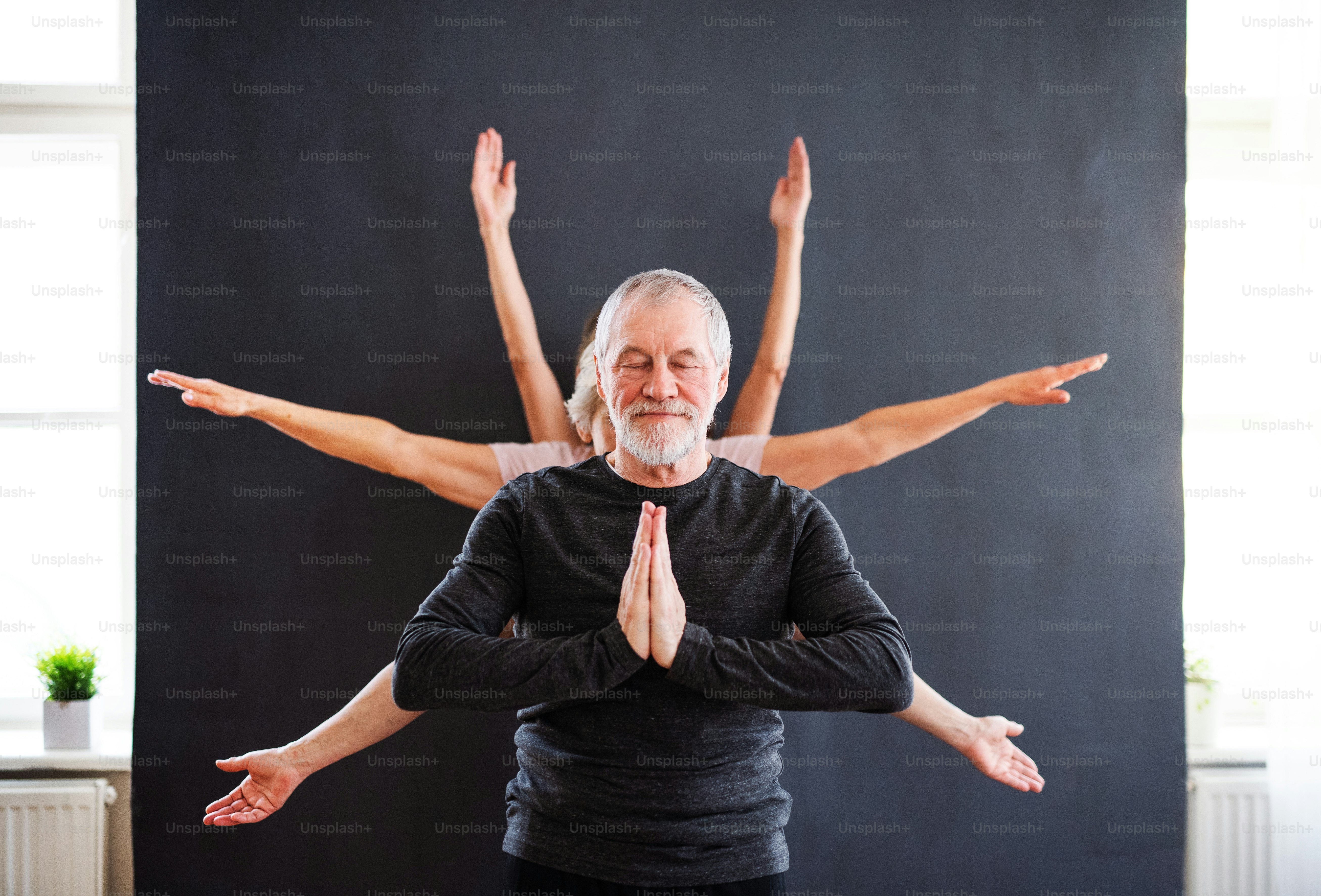 A senior man with multiple arms doing yoga exercise in community center ...