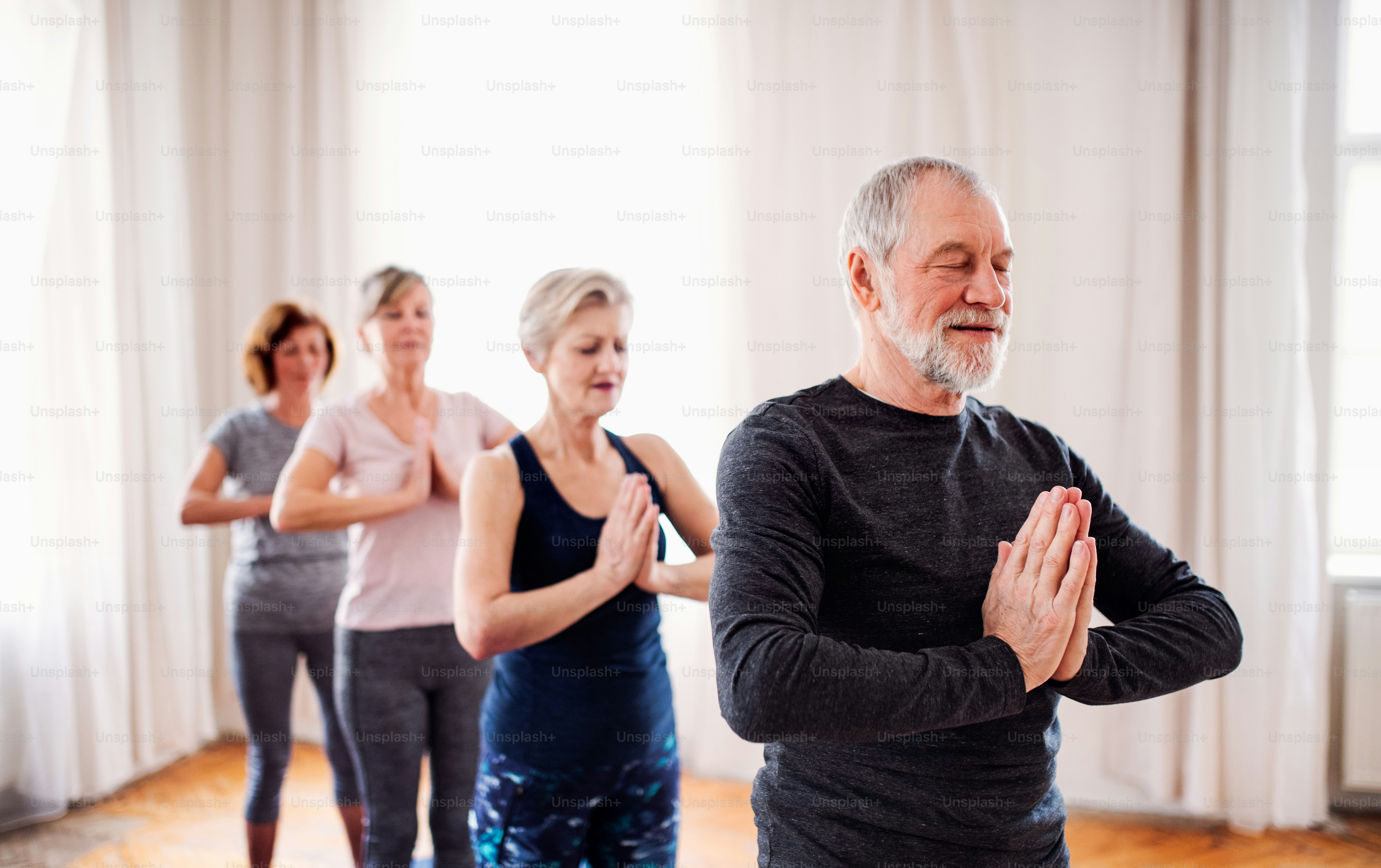 Group of active senior people doing yoga exercise in community center ...