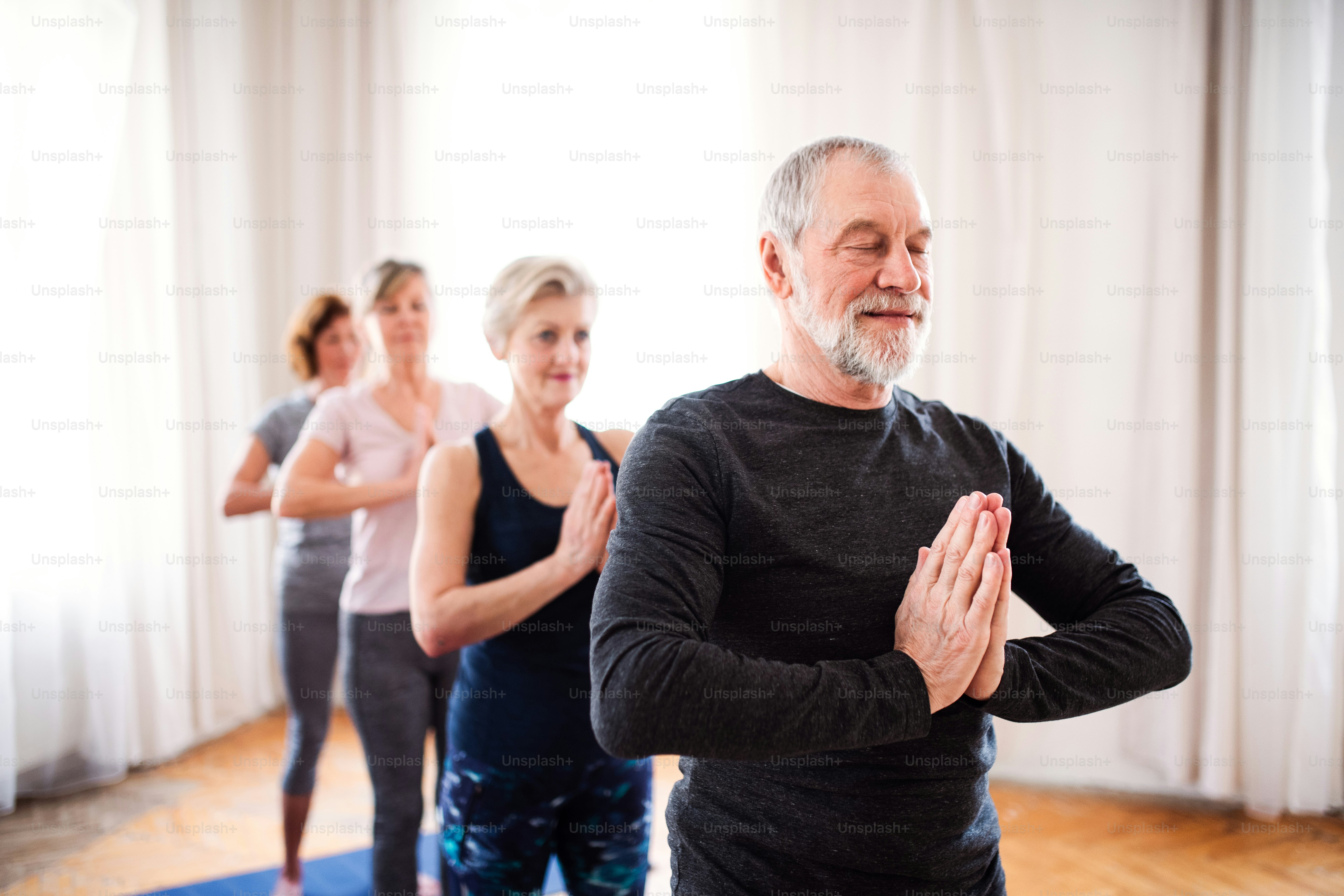 Group of active senior people doing yoga exercise in community center ...