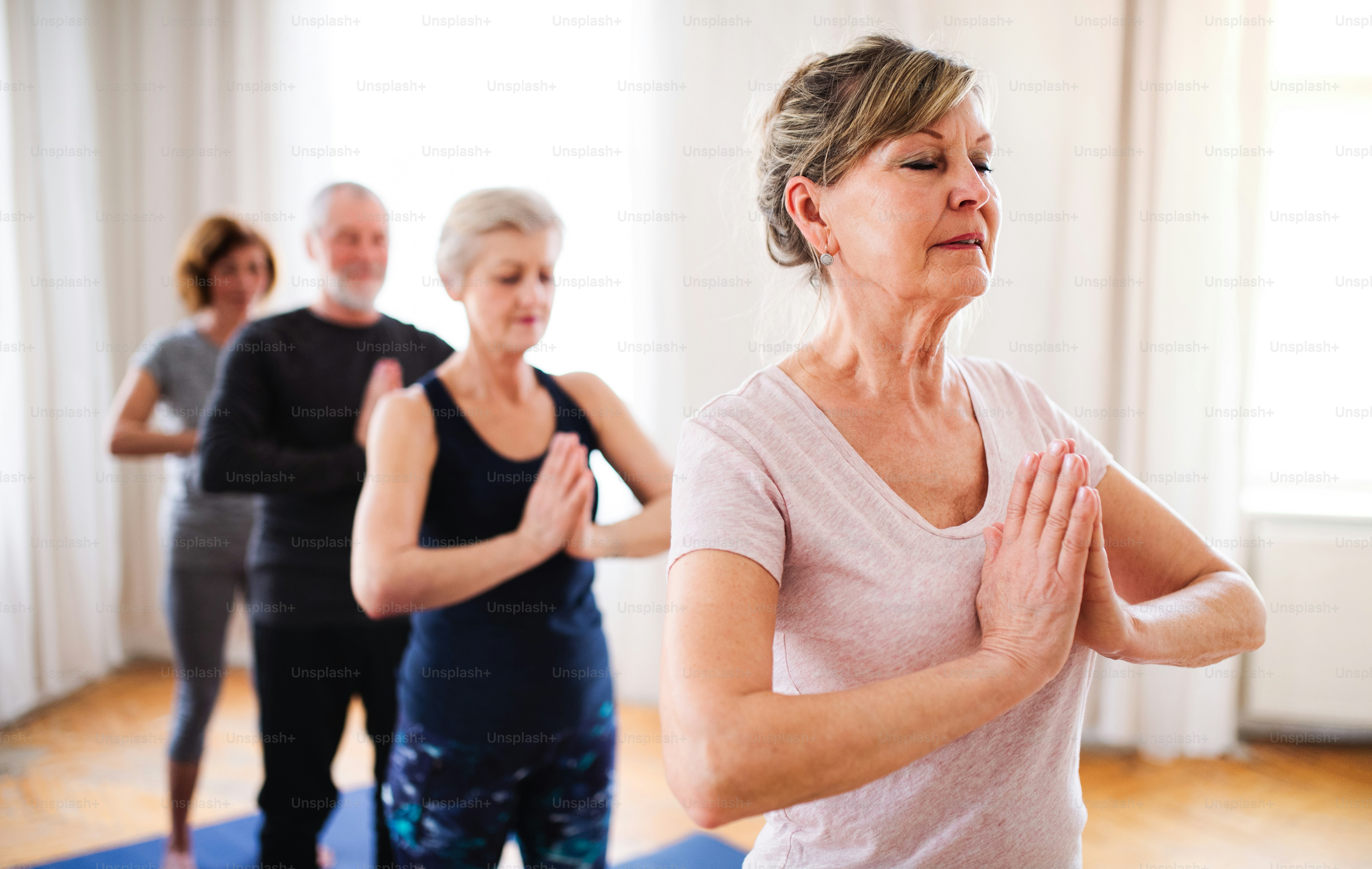 Group of active senior people doing yoga exercise in community center ...