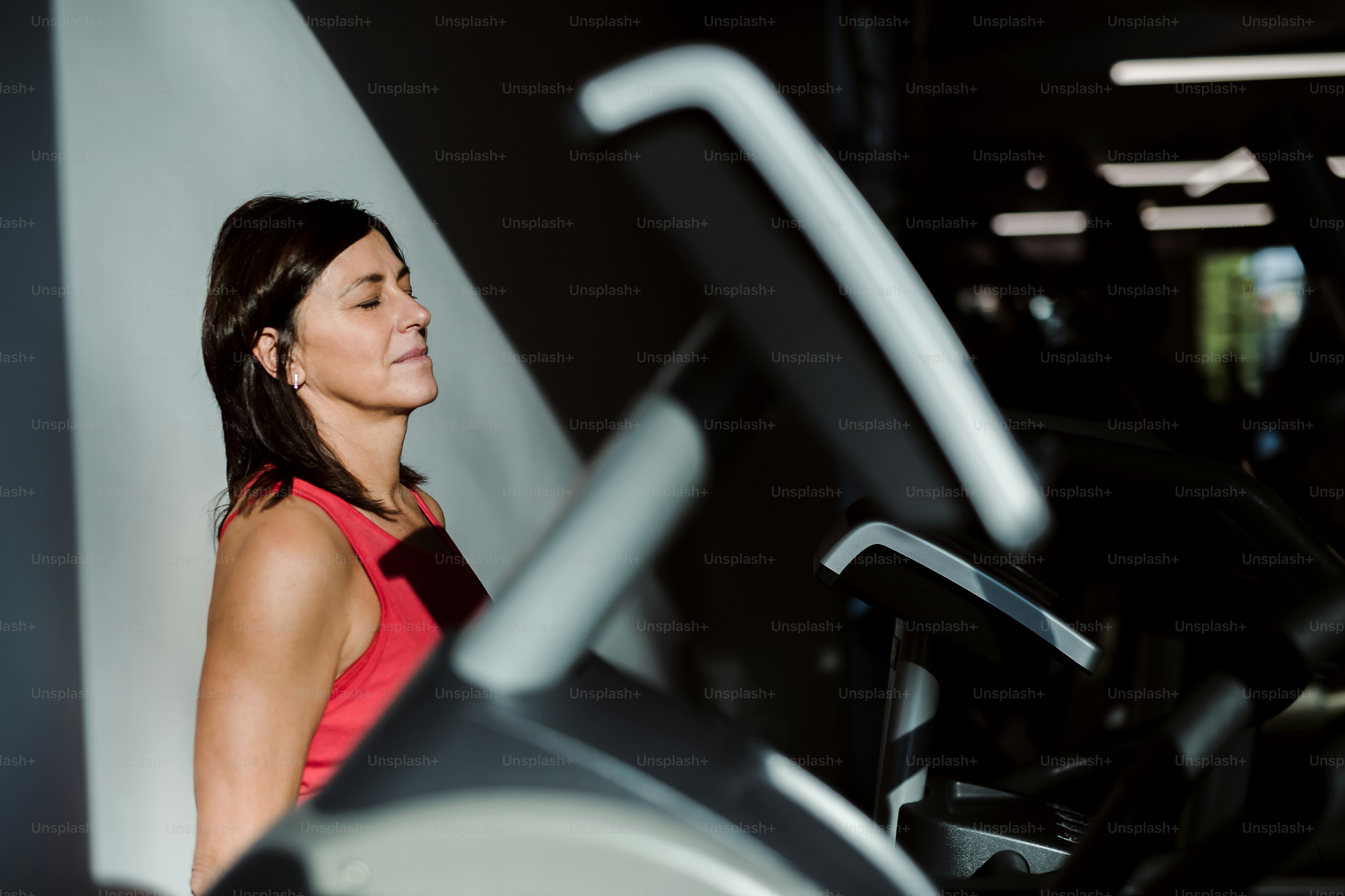 A content senior woman in gym resting after doing exercise, eyes closed ...