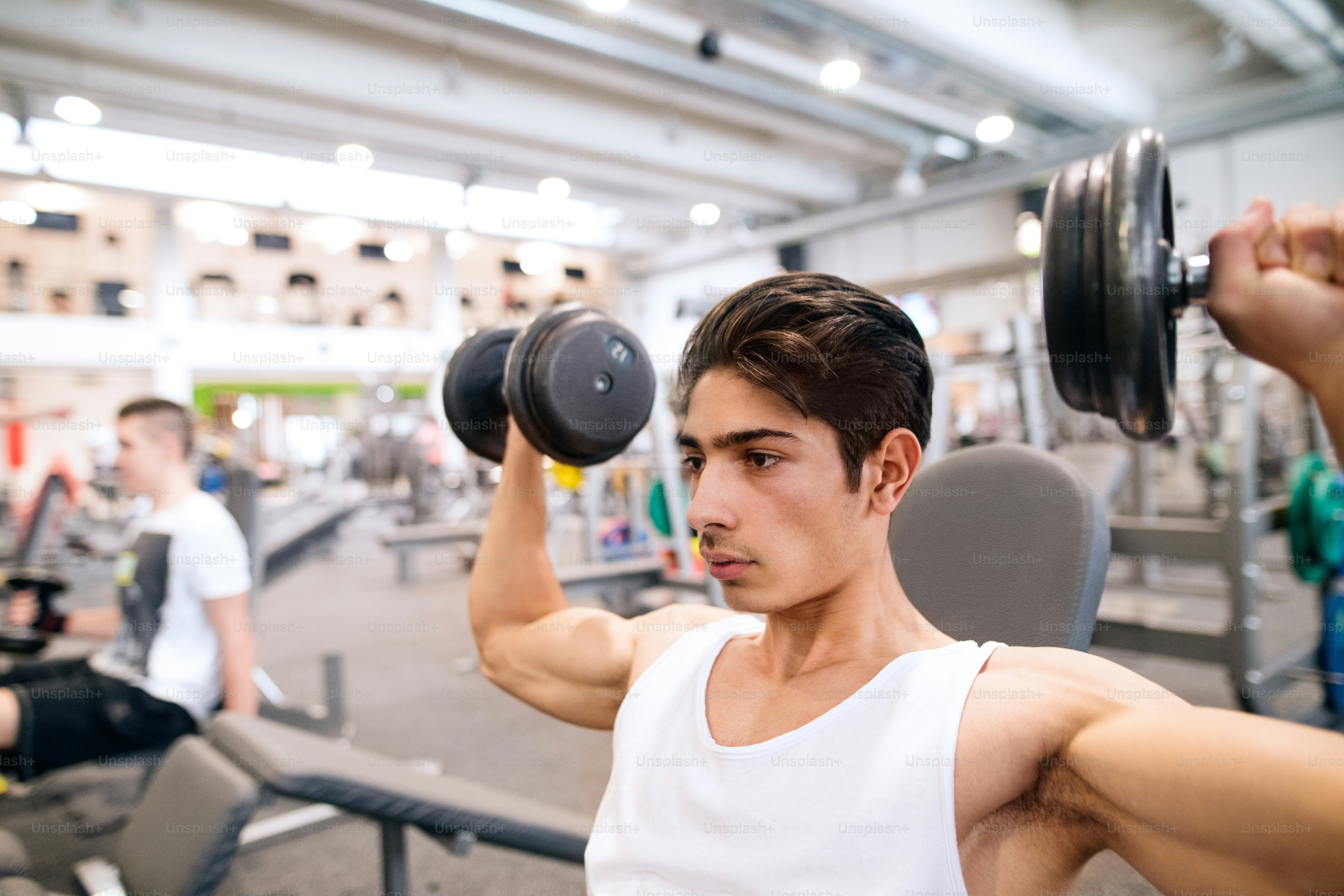Young hispanic fitness man in gym on bench, working out with weights ...