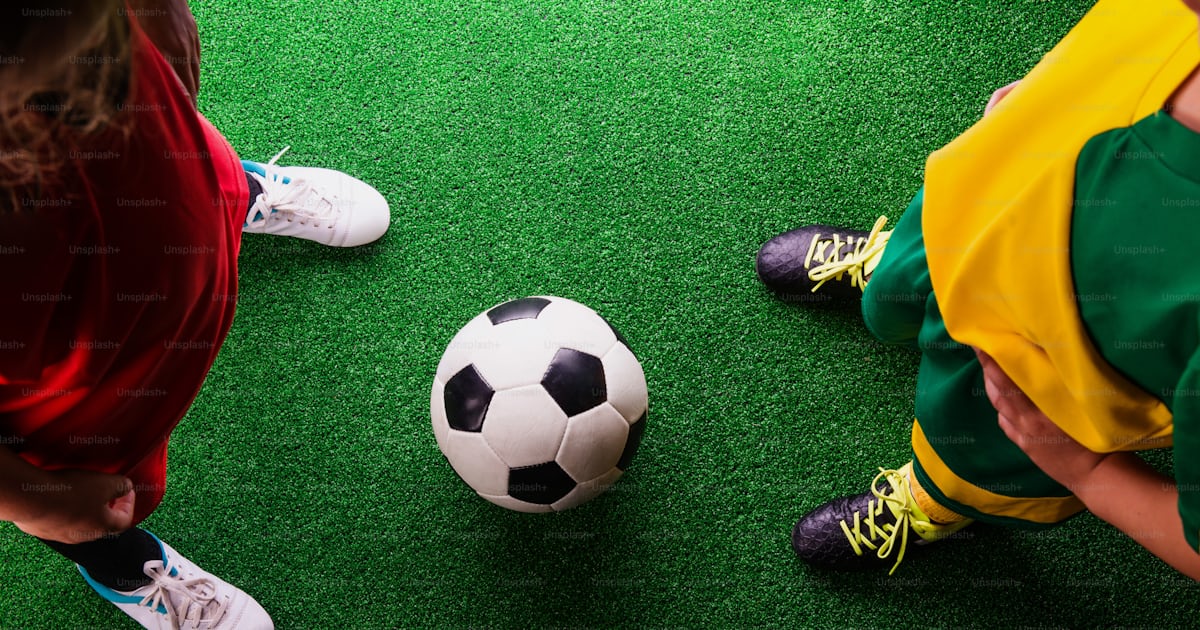인조 잔디에 축구공을 가진 두 명의 알아볼 수 없는 작은 축구 선수의 다리 스튜디오는 녹색 배경에 촬영했습니다 사진