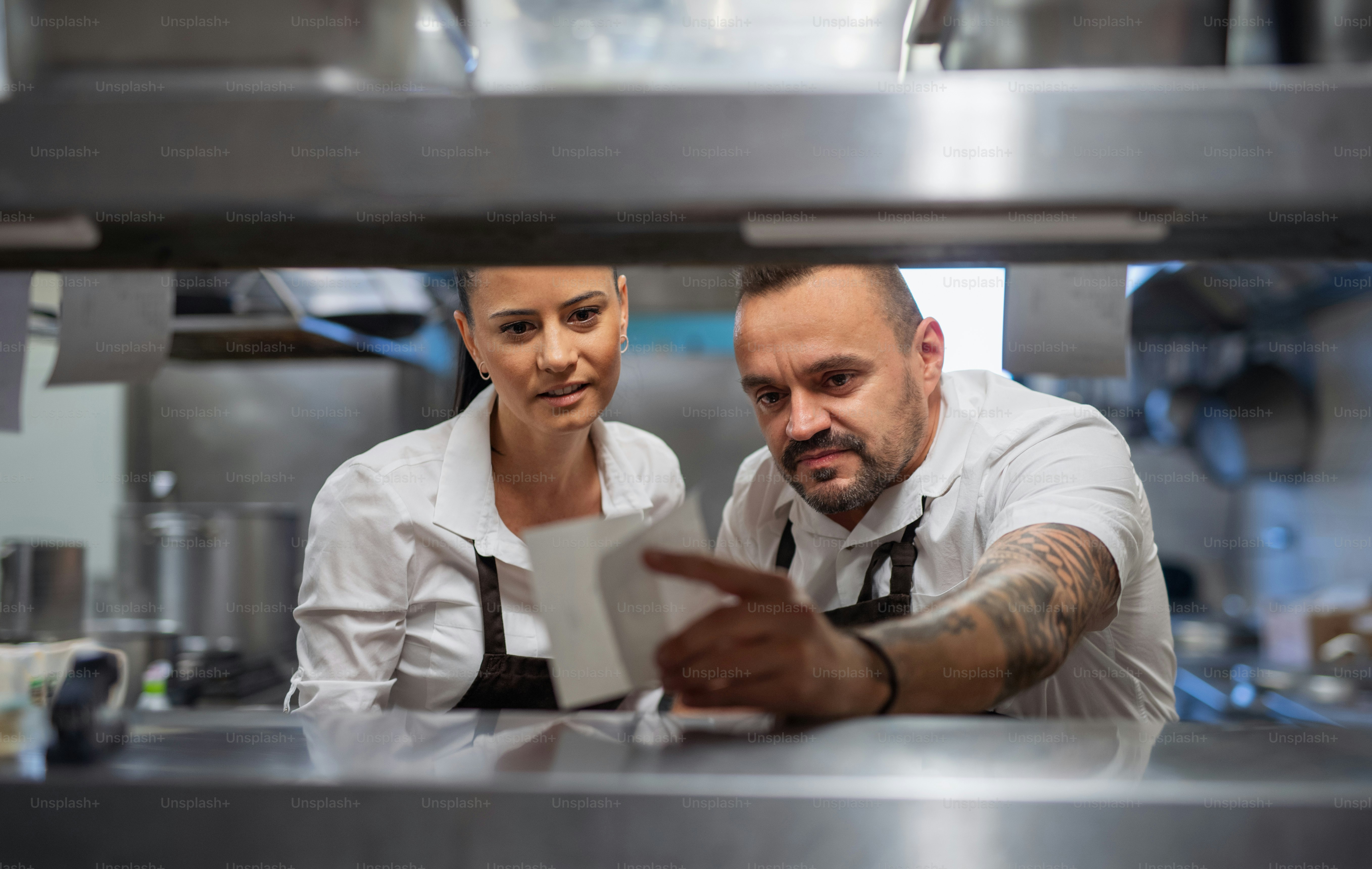 A chef and cook taking order slip in commercial kitchen. photo ...
