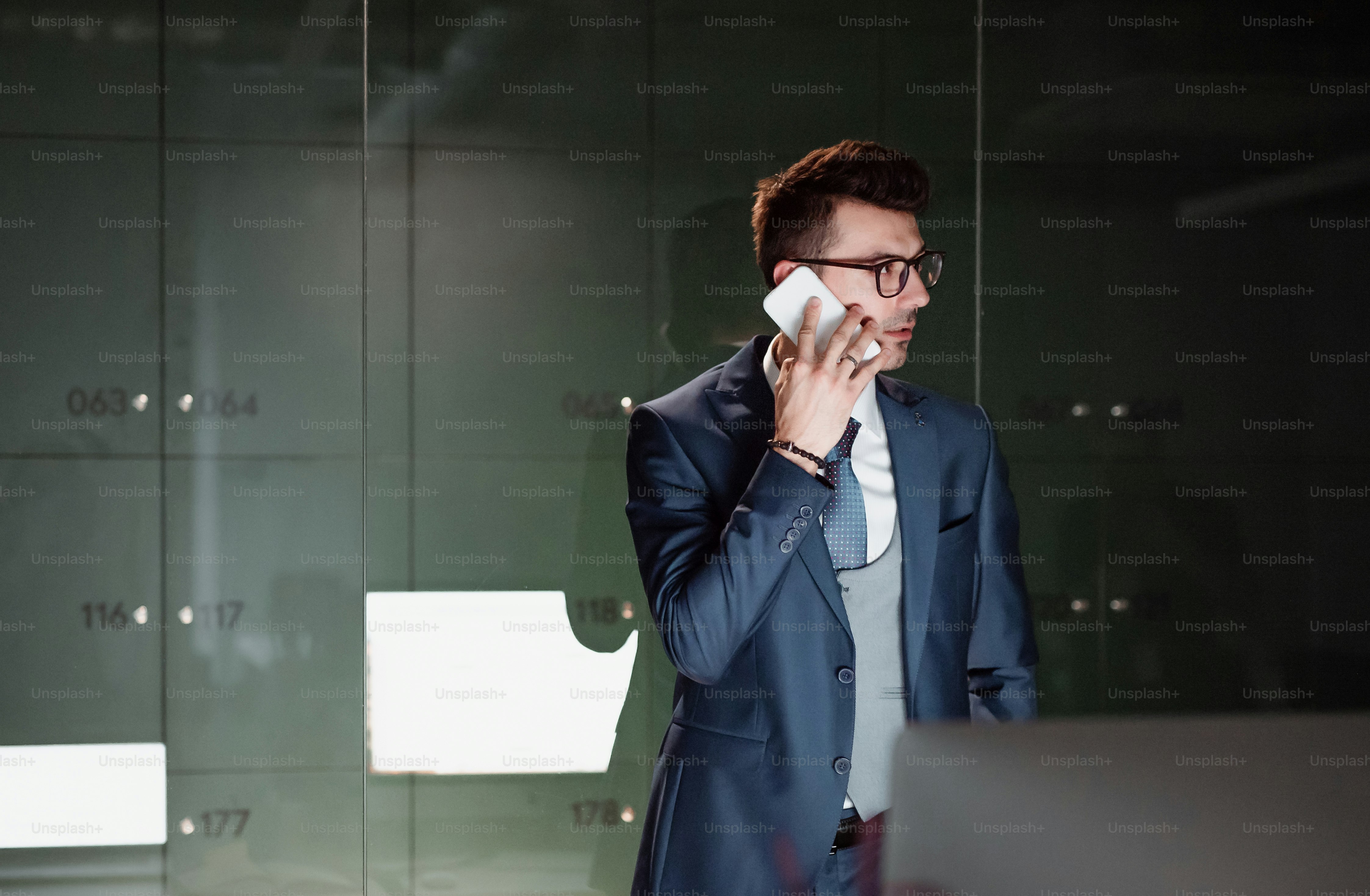 A portrait of young businessman with smartphone standing by lockers in ...