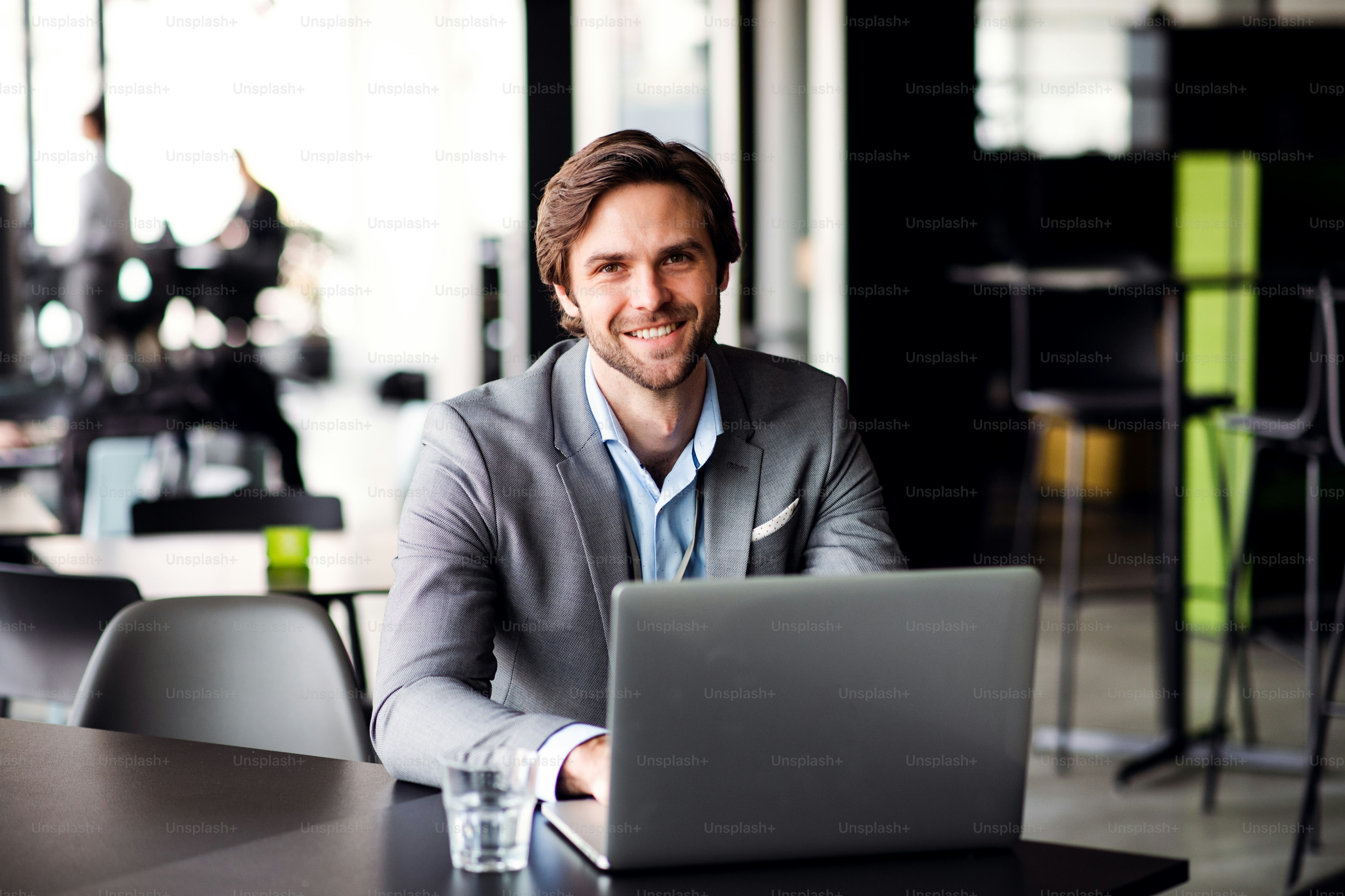 A portrait of happy young businessman with computer in an office ...