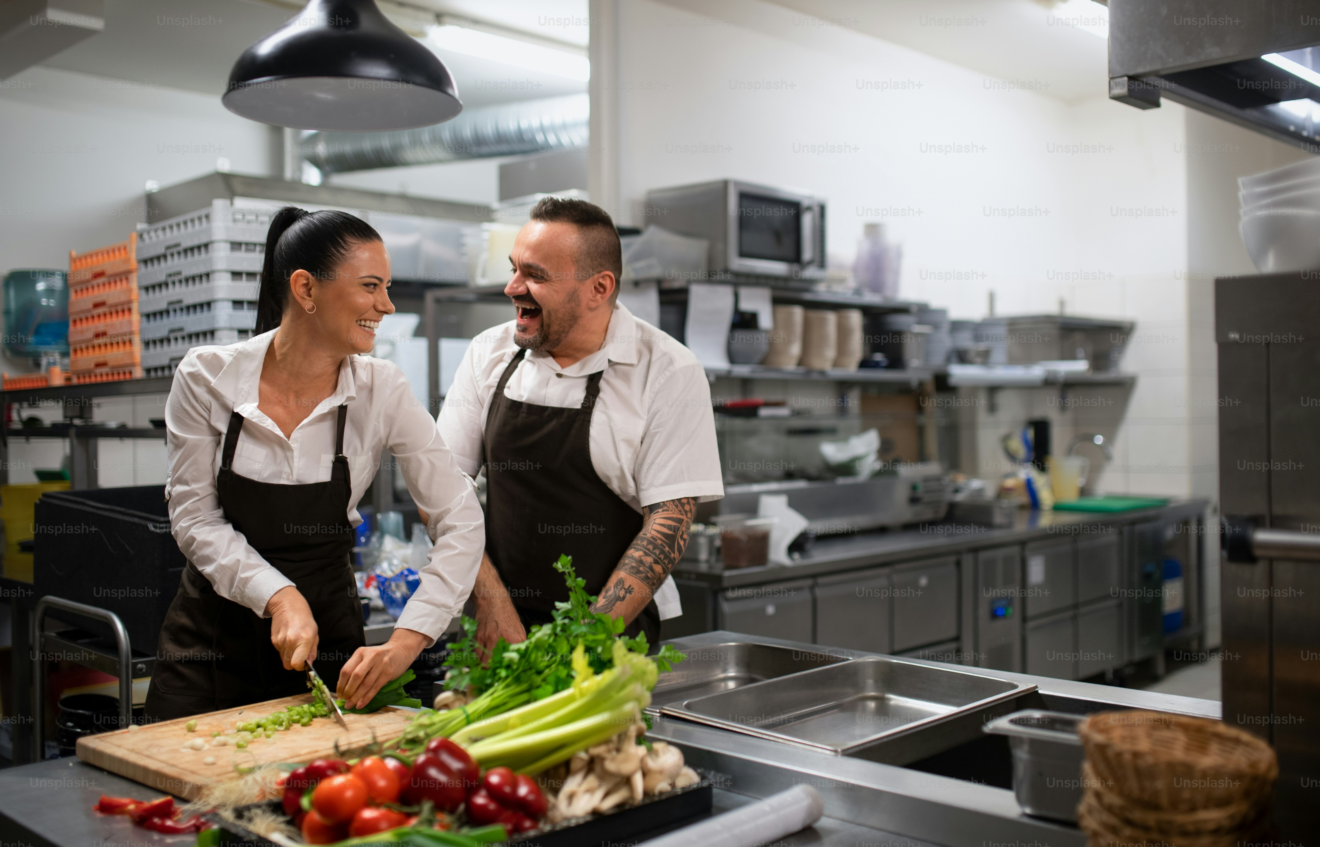 A chef teaching how to cook, cutting vegetables indoors in commercial ...