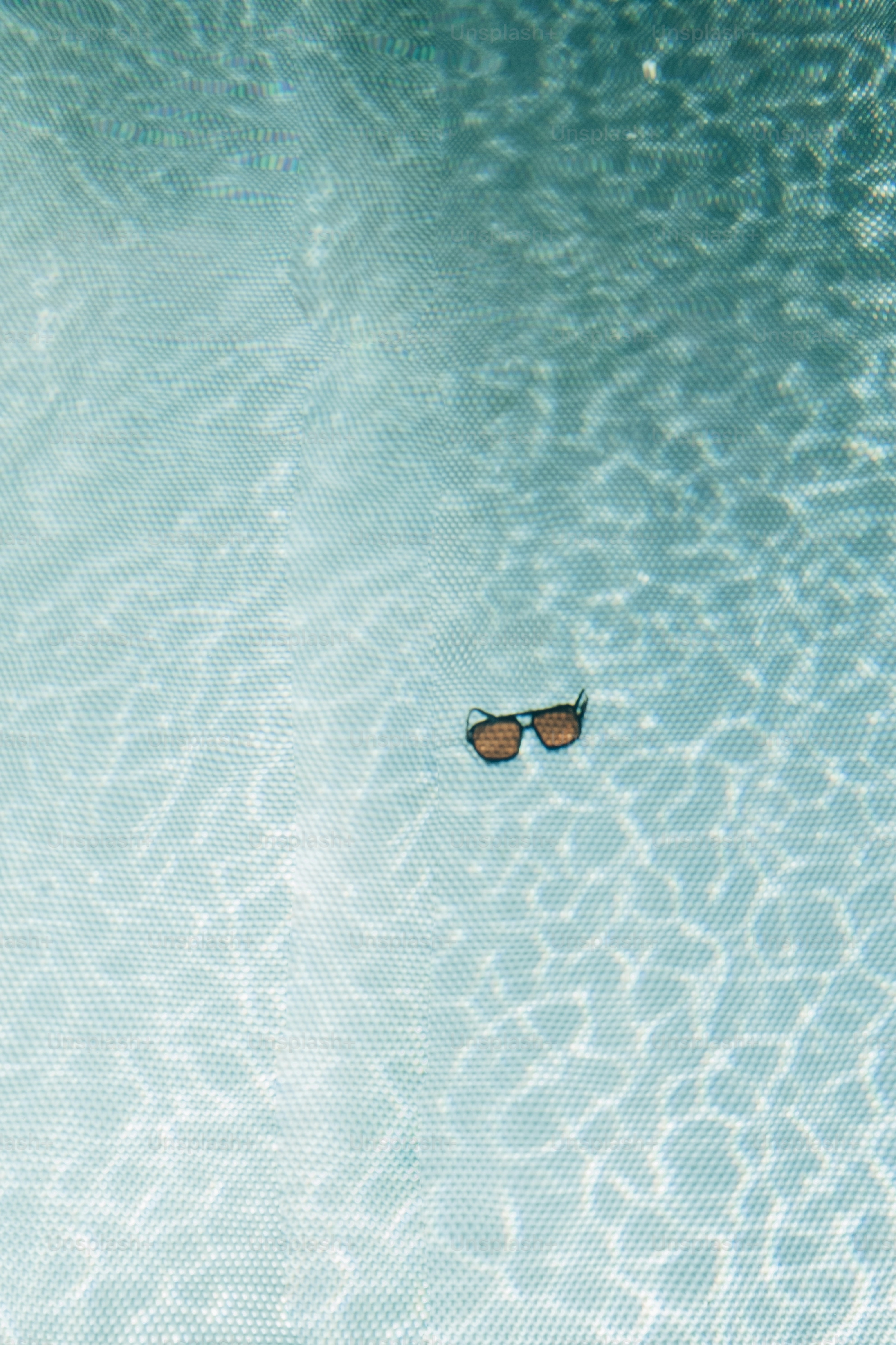 A pair of sunglasses floating in a pool of water photo – Summer ...
