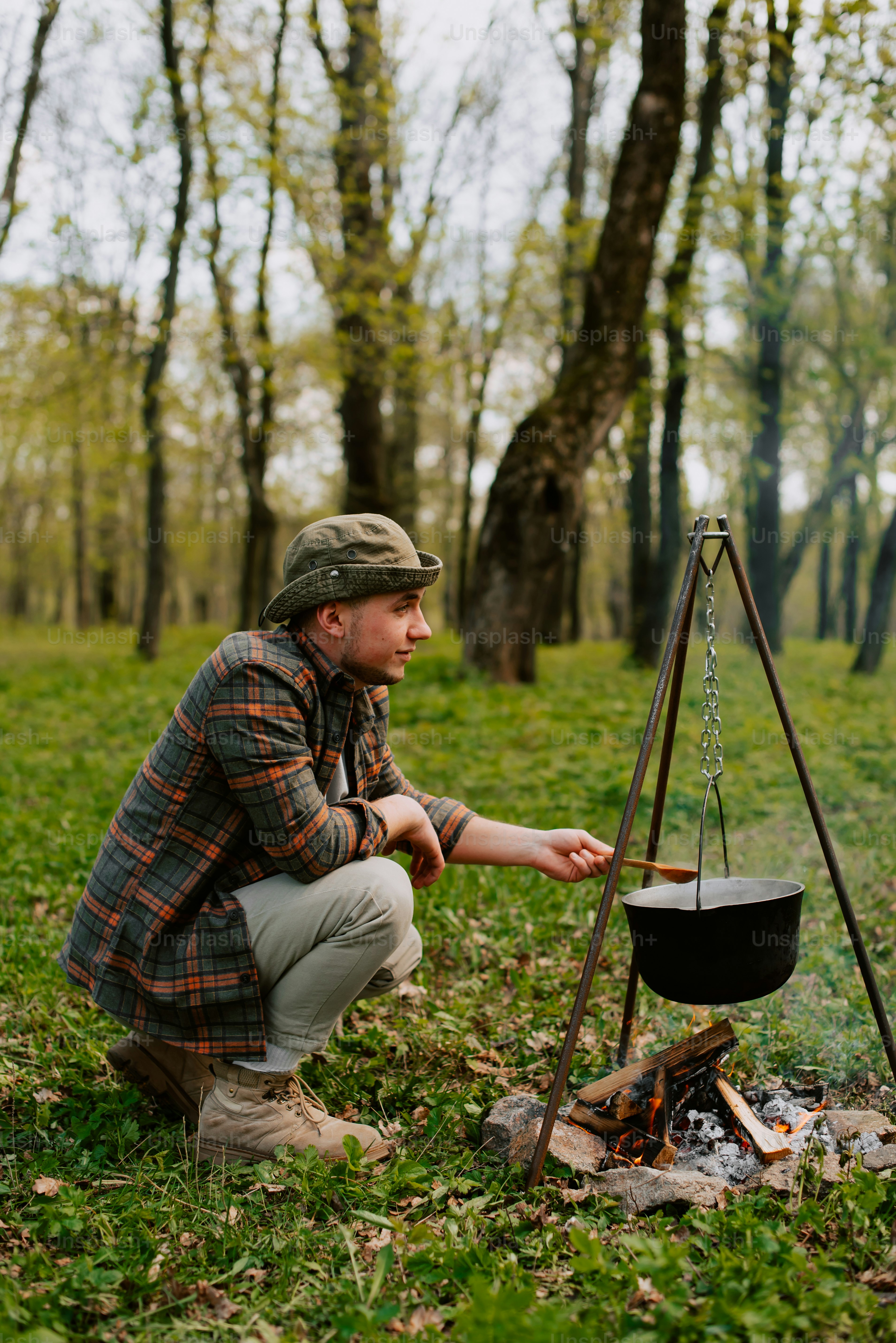 A man cooking food over an open fire in the woods photo – Camping Image ...