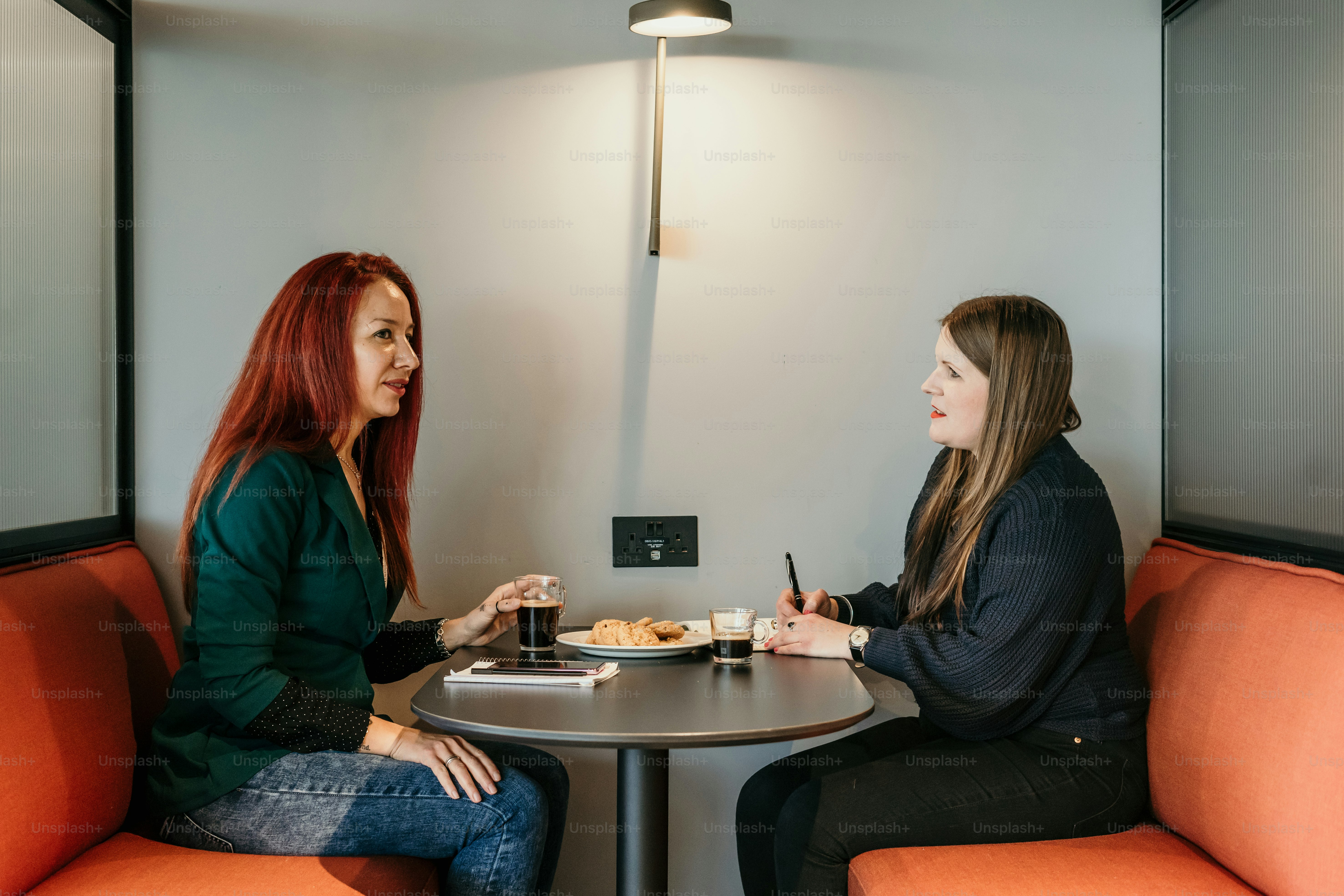Two women sitting at a table having a conversation photo ...