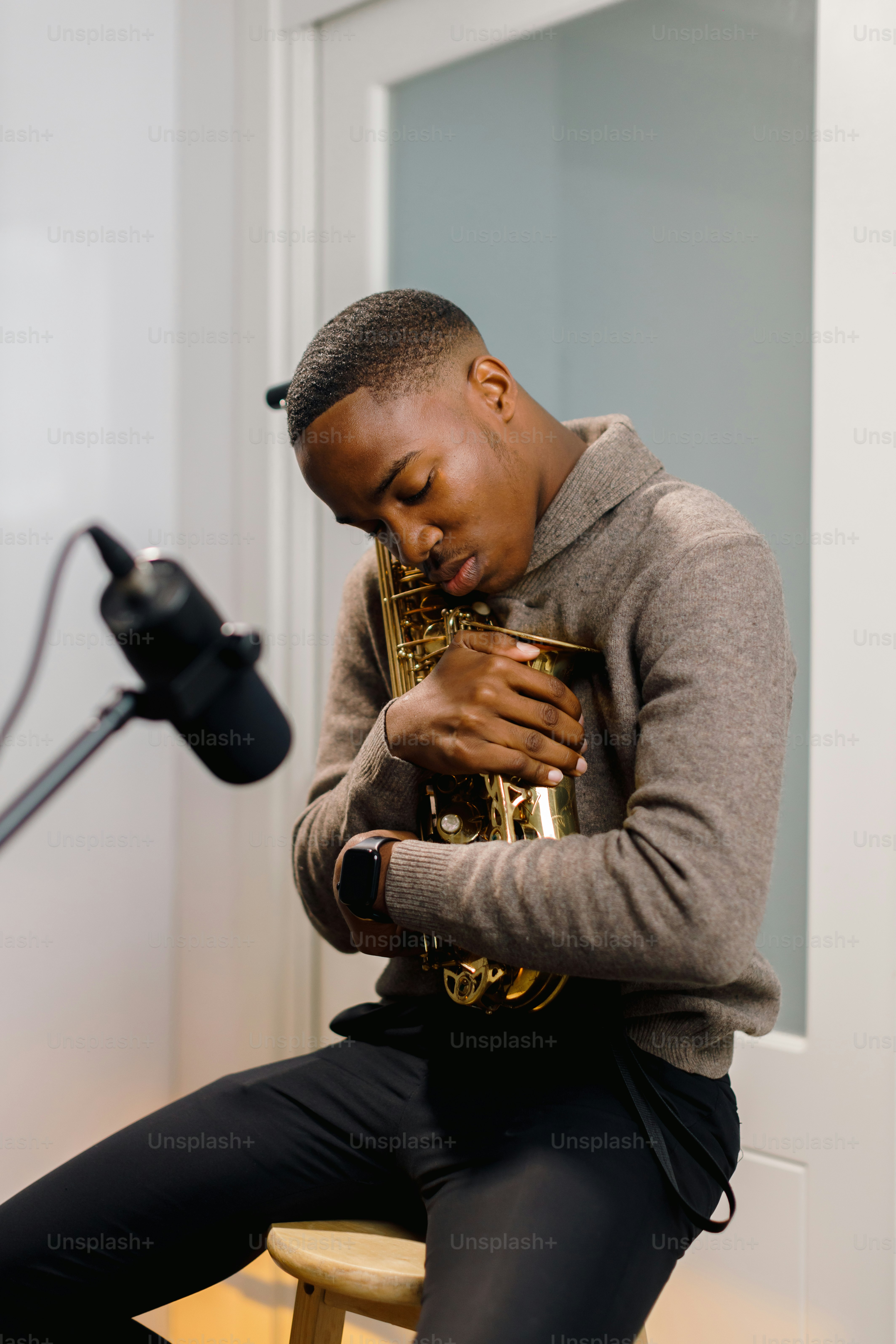 A man sitting on a stool holding a saxophone photo – Saxophone Image on ...