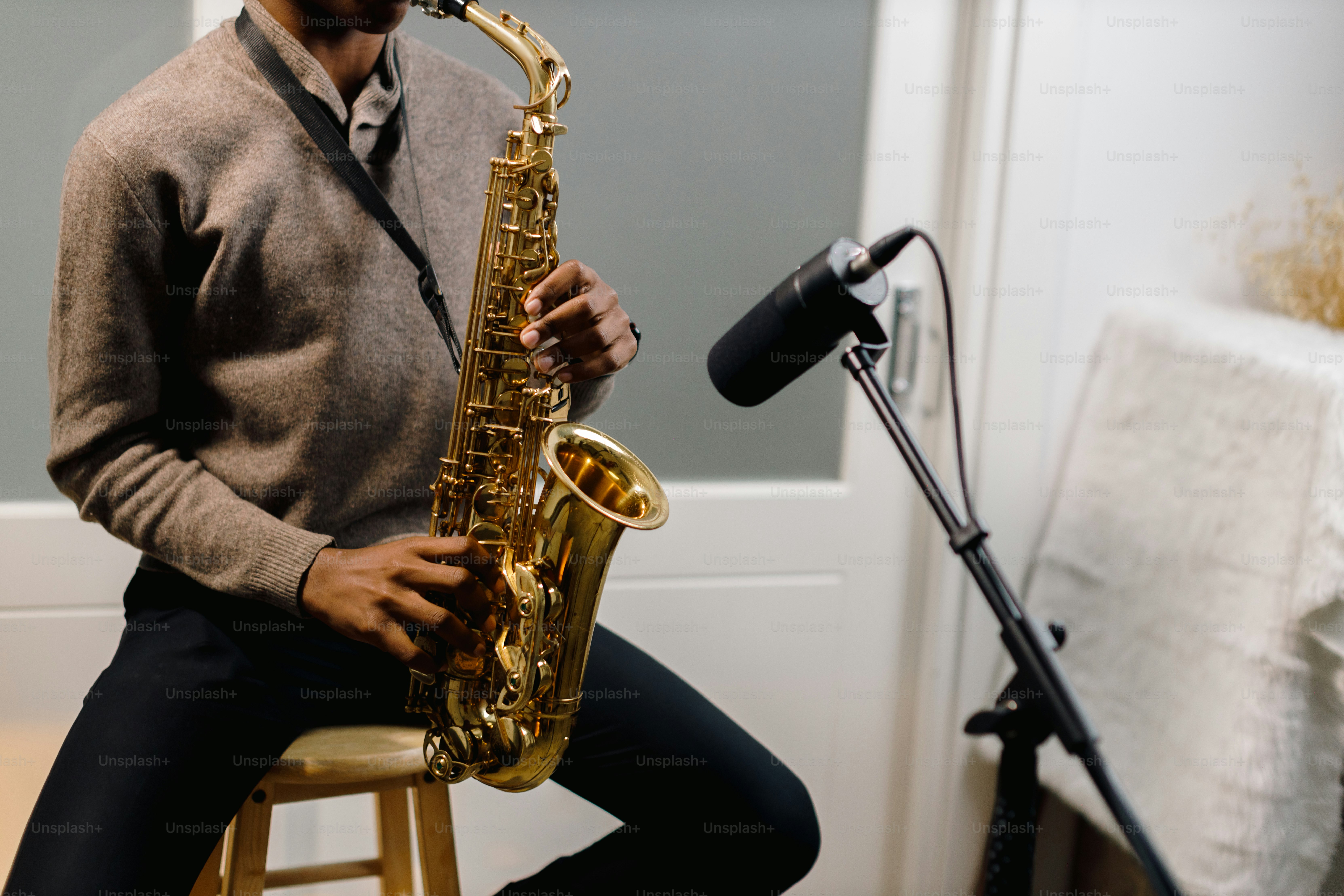 A man playing a saxophone in front of a microphone photo – Saxophone ...