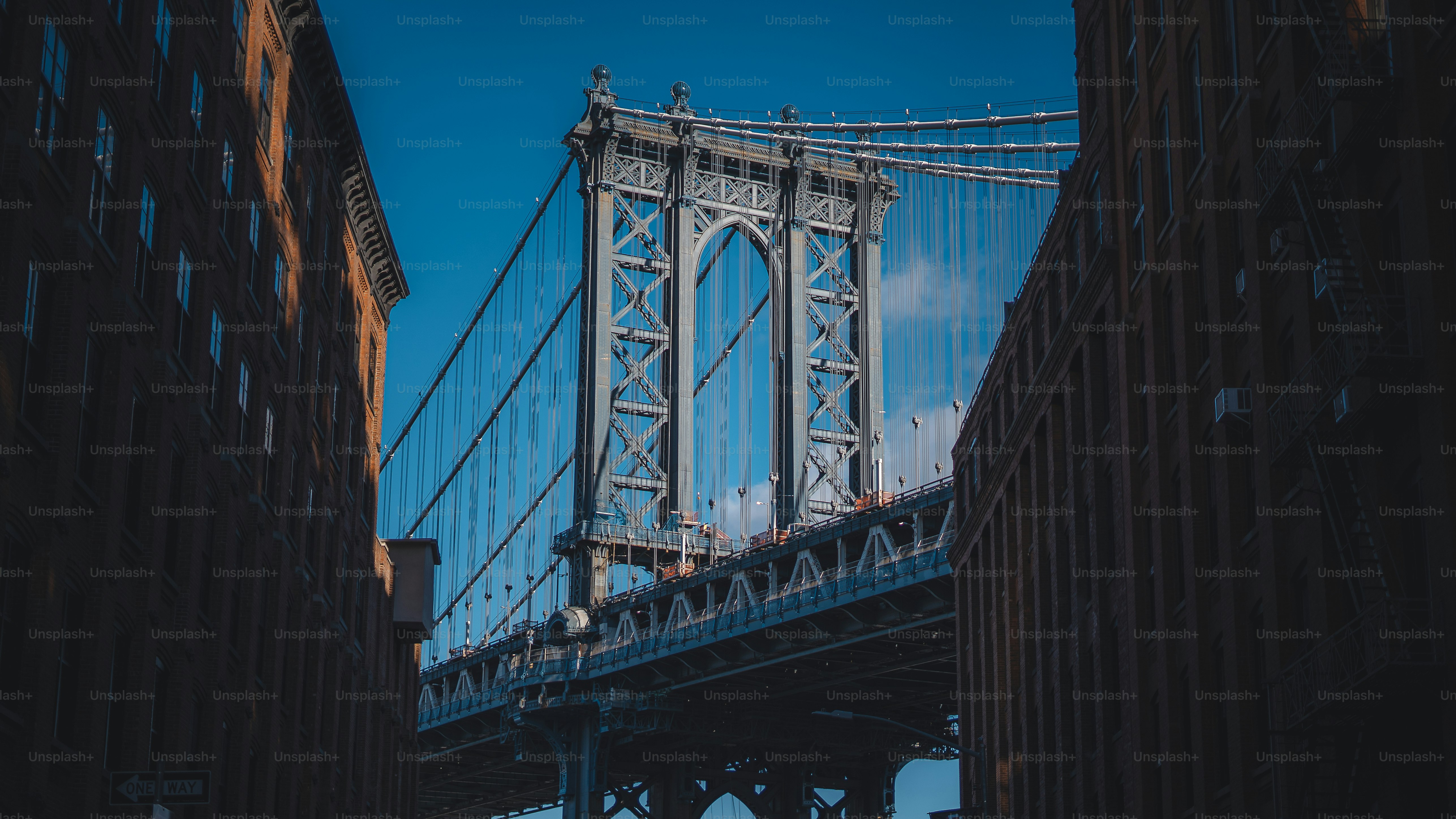 A view of a bridge from between two buildings photo – Brooklyn bridge ...