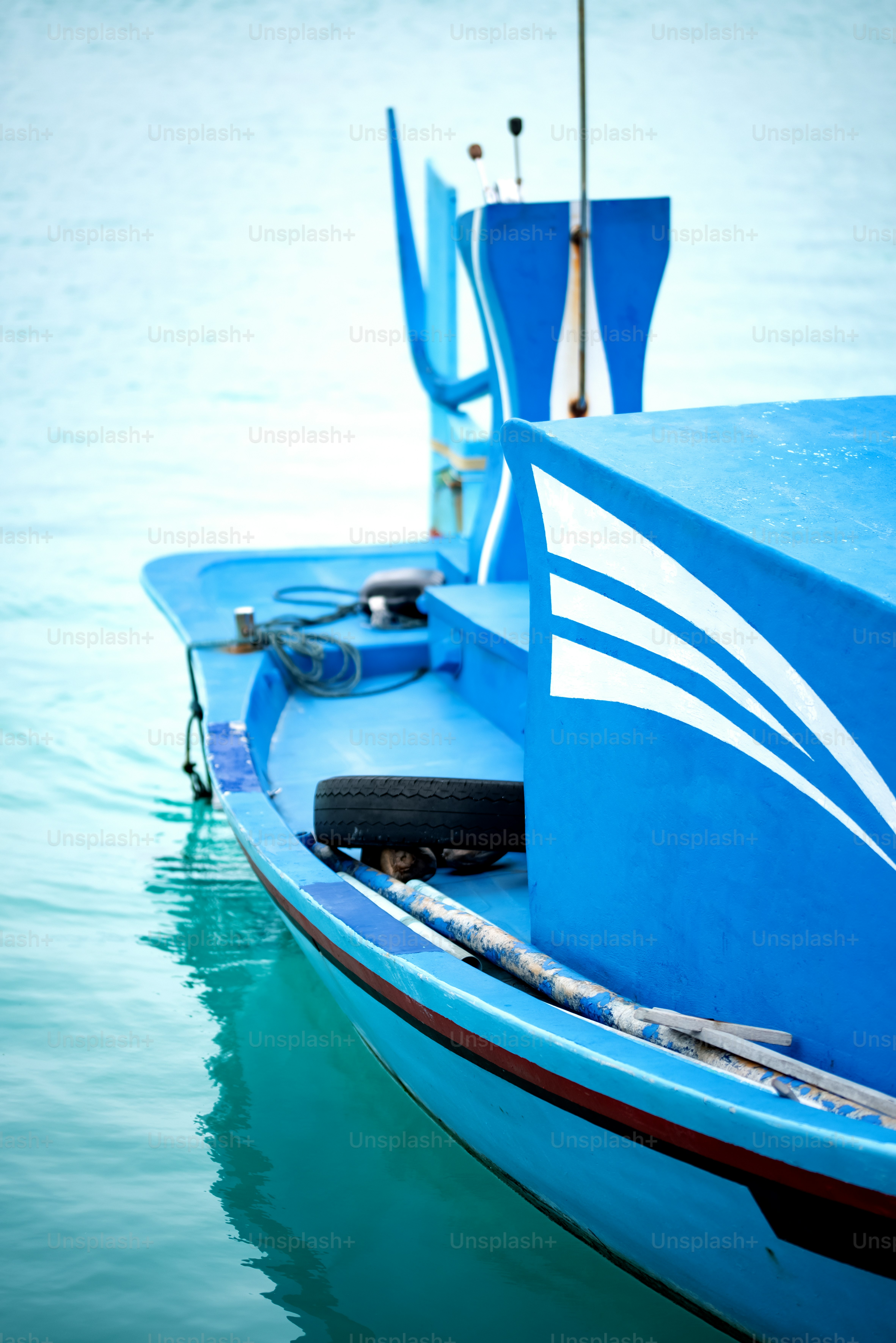 A small blue boat floating on top of a body of water photo – Maldives ...