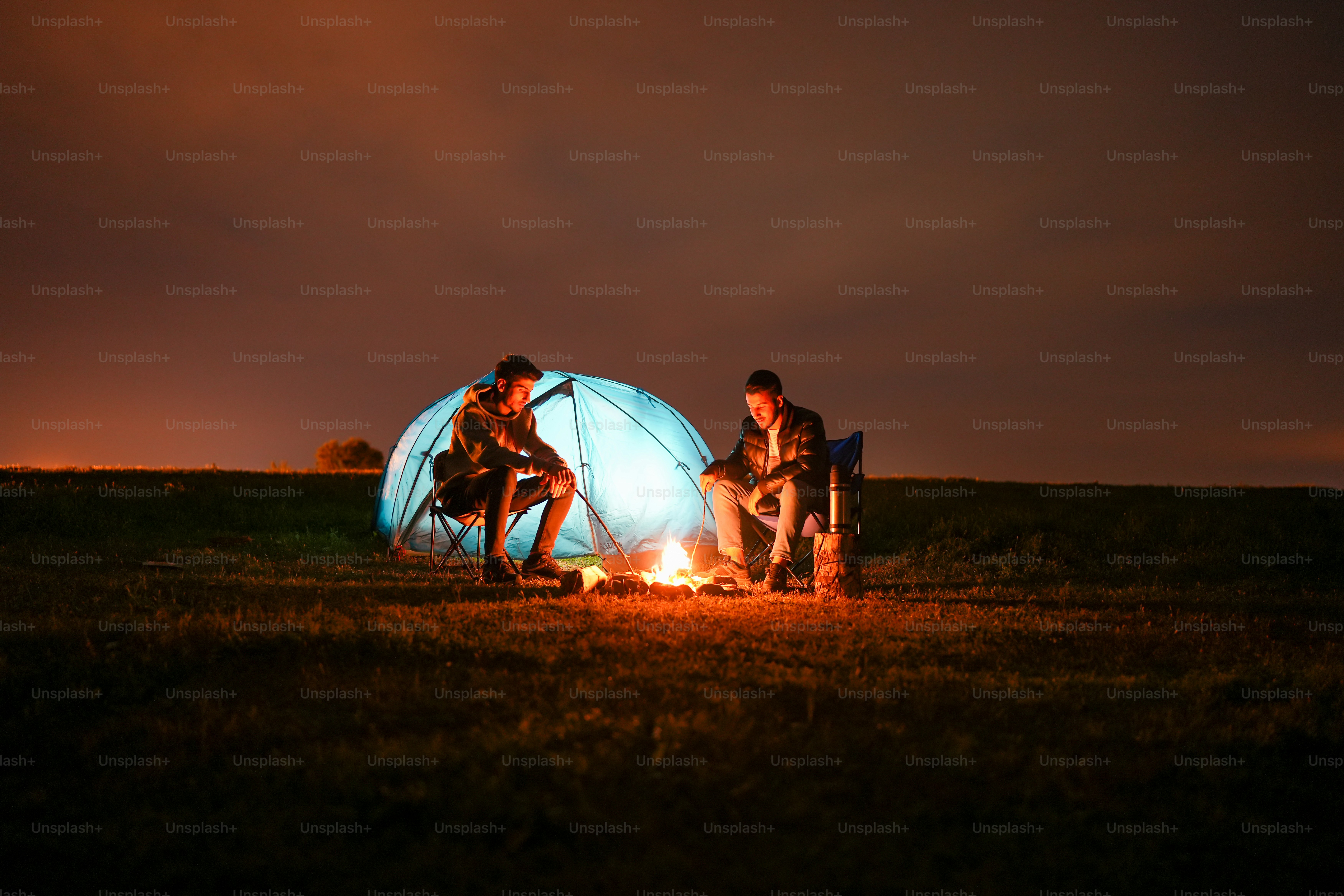 Trois personnes assises autour d’un feu de camp la nuit photo – En ...