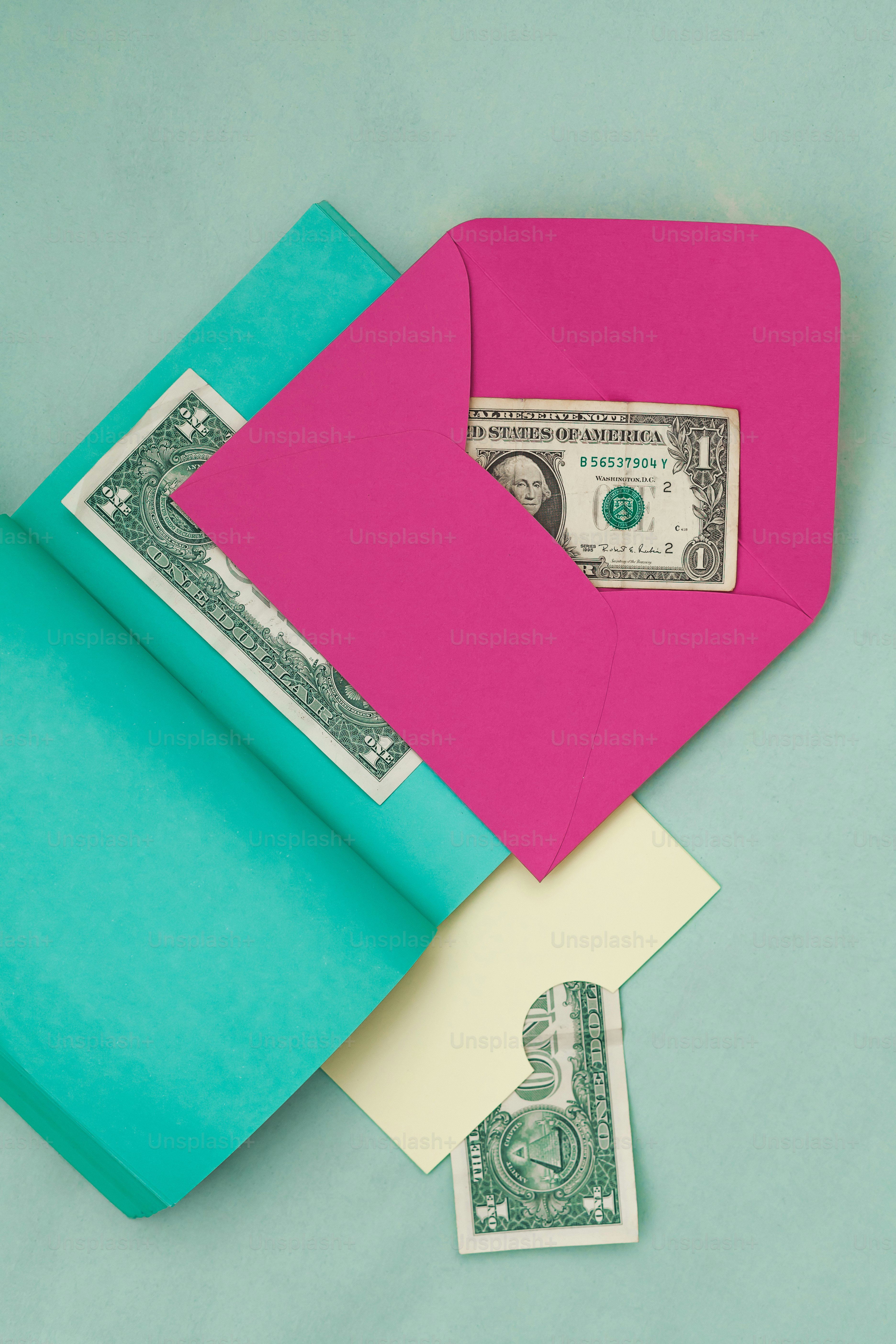 A pink envelope with a dollar bill sticking out of it photo – Us dollar ...