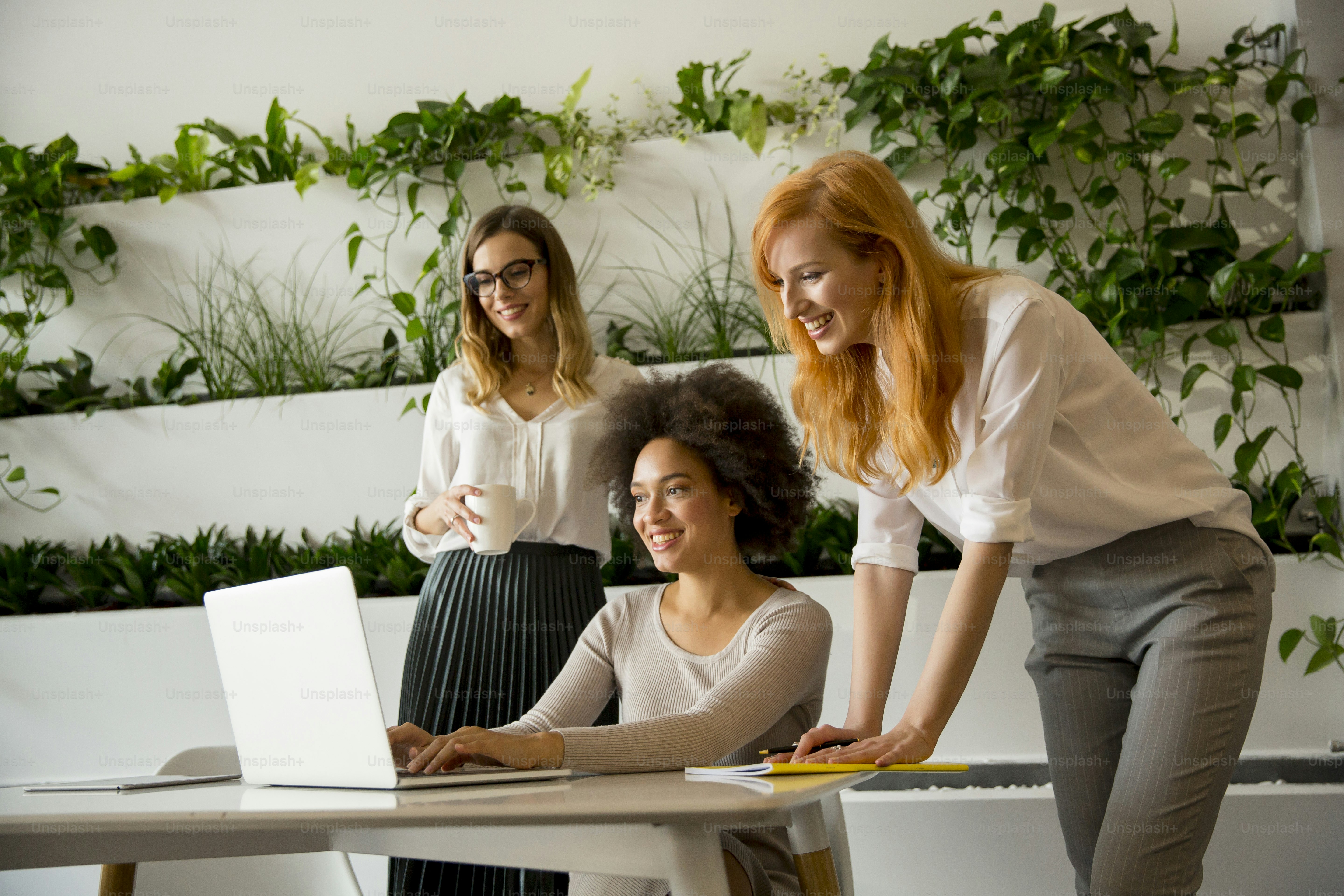 Cheerful professional multiracial women working and presenting data in ...