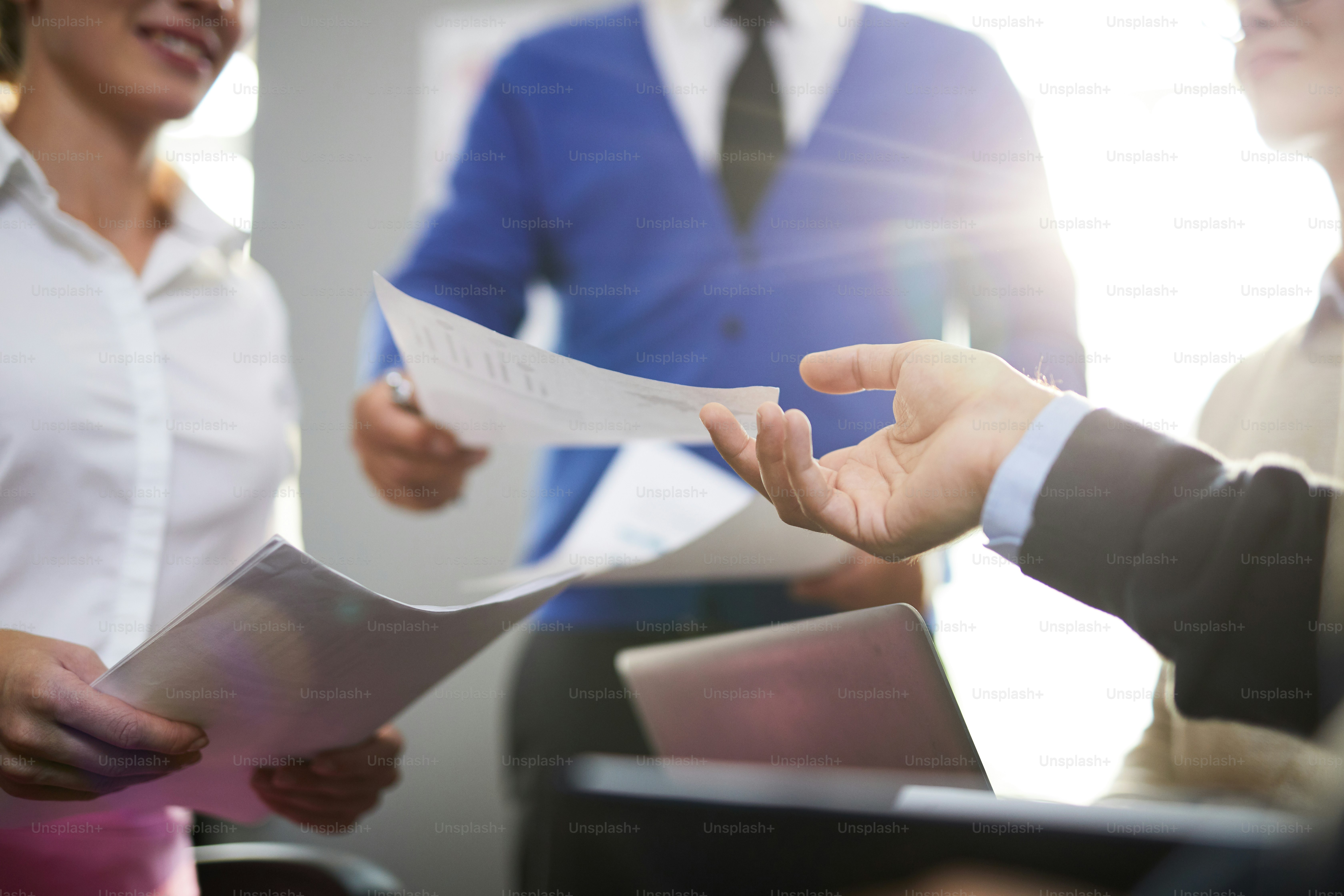 Businessman passing paper over to one of colleagues while discussing ...