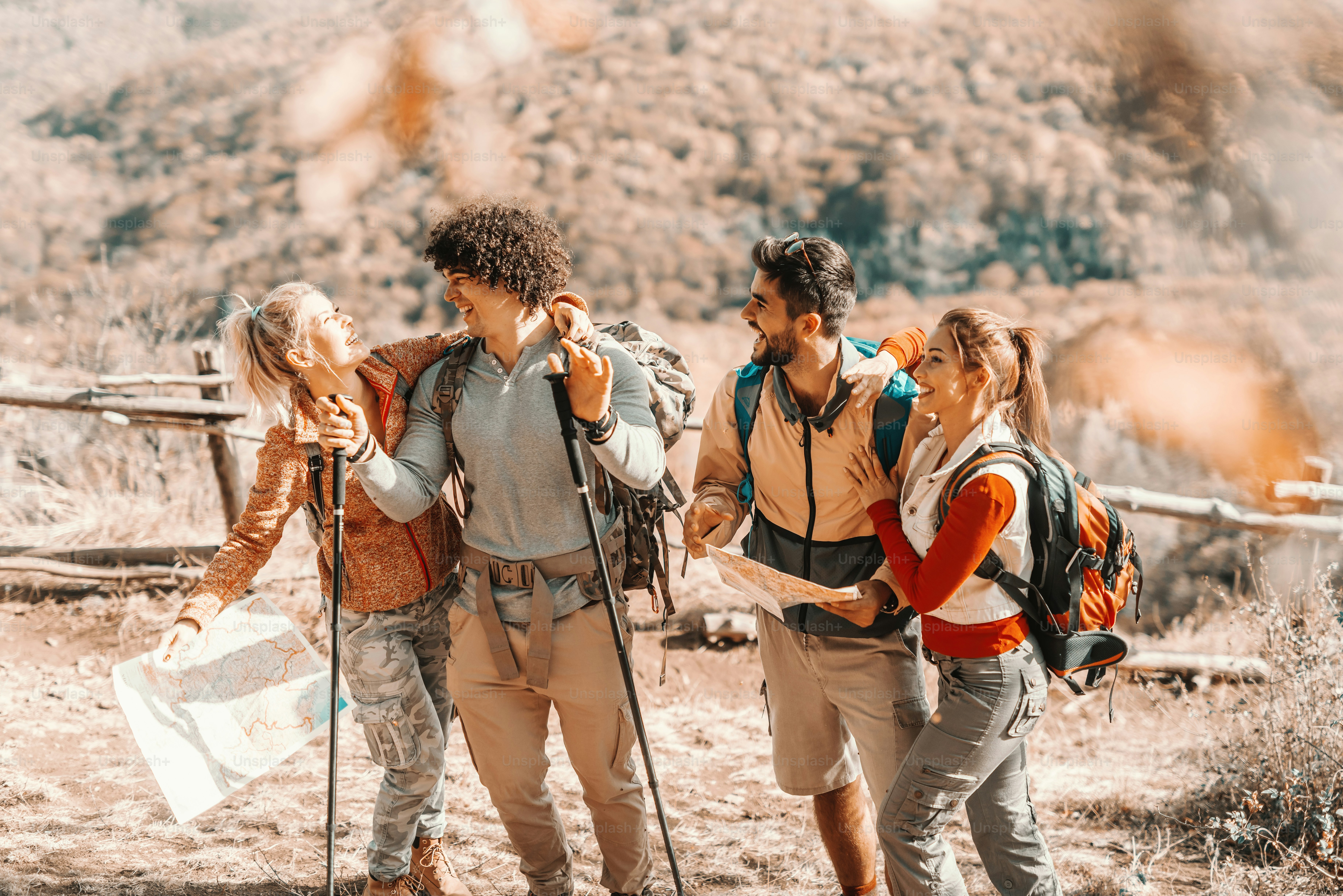 Four happy hikers standing on the glade and enjoying nature in autumn ...