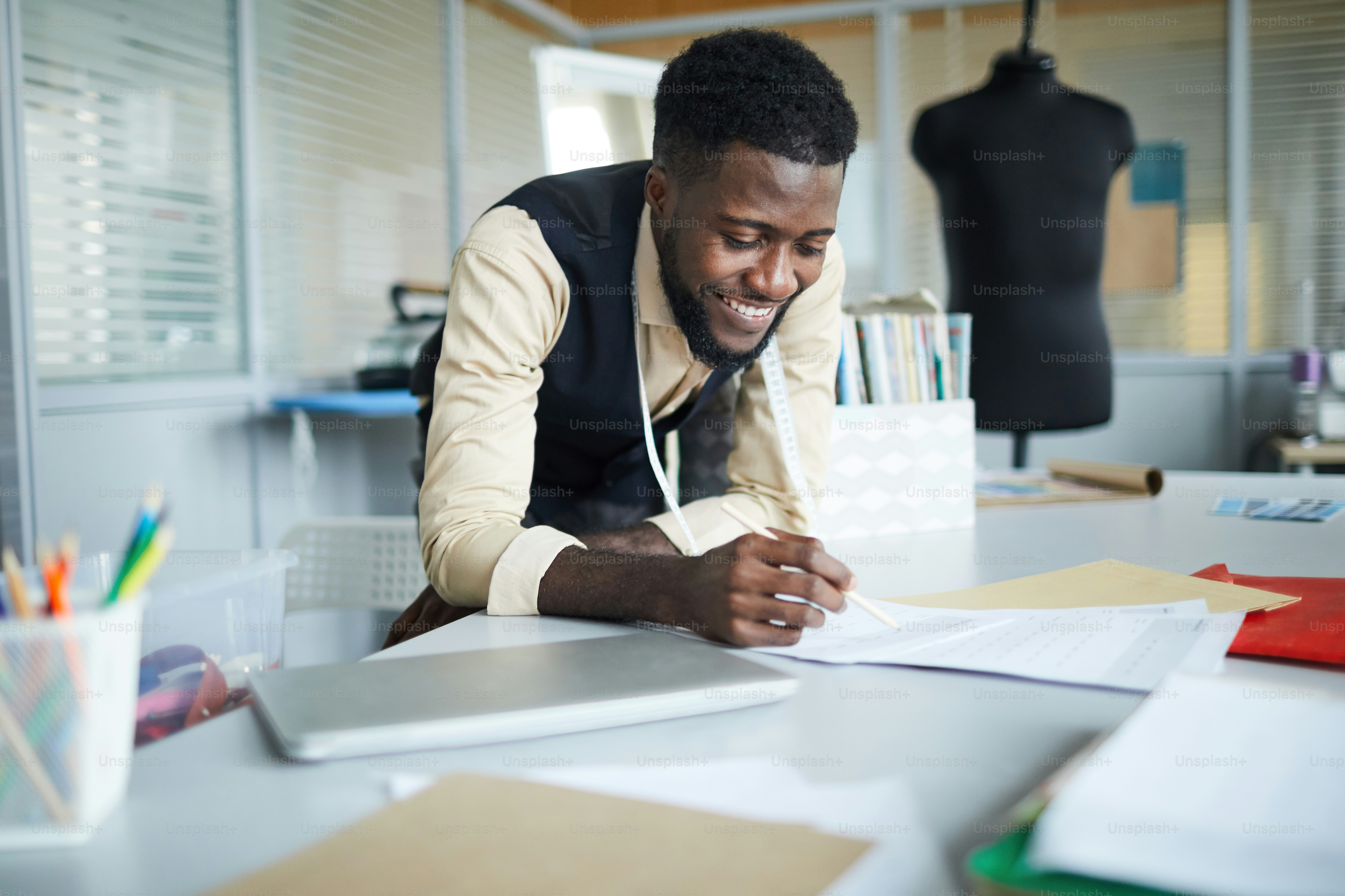 Successful tailor leaning over table while reading paper during work in ...