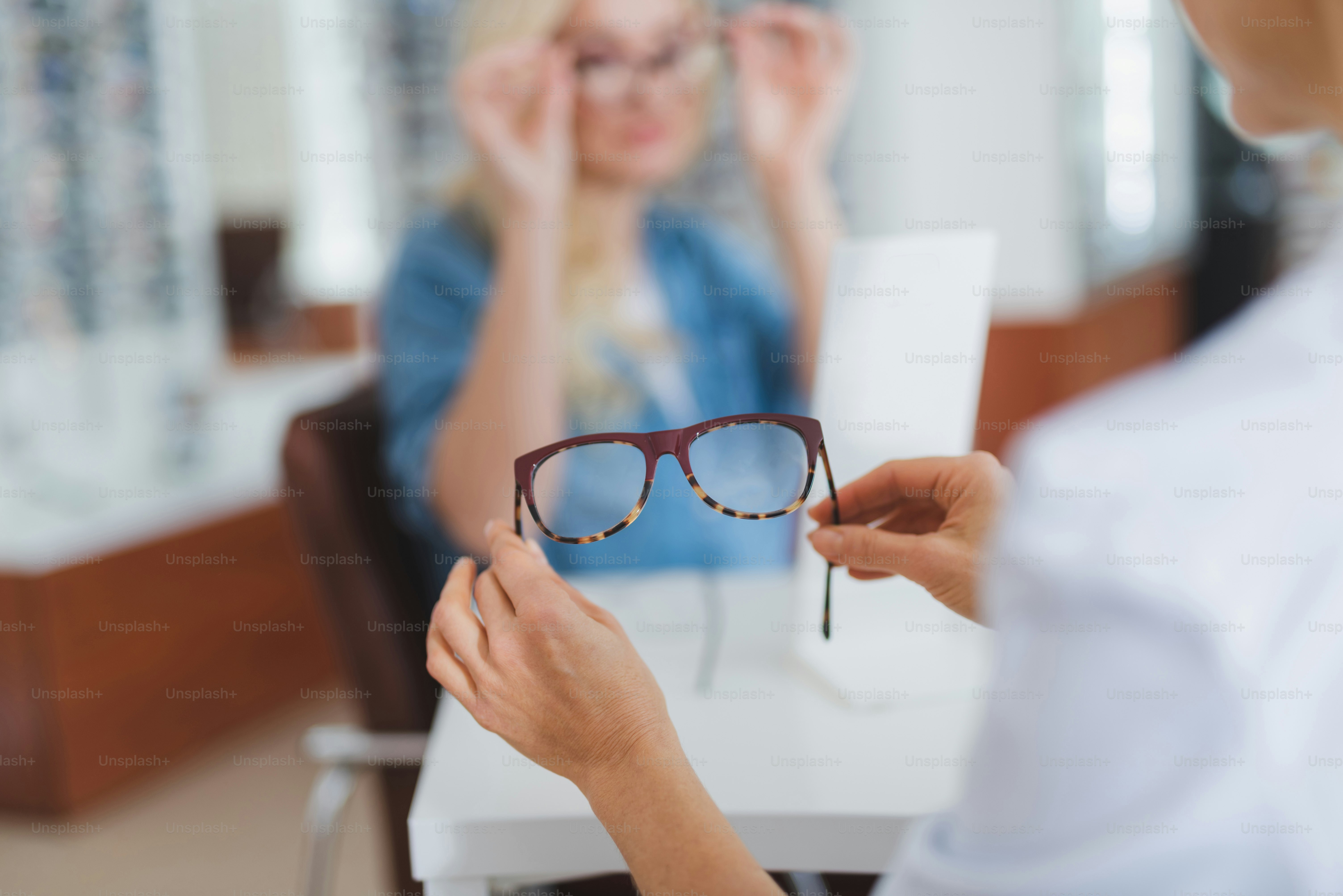 Nice female optician giving glasses to her customer while working at ...