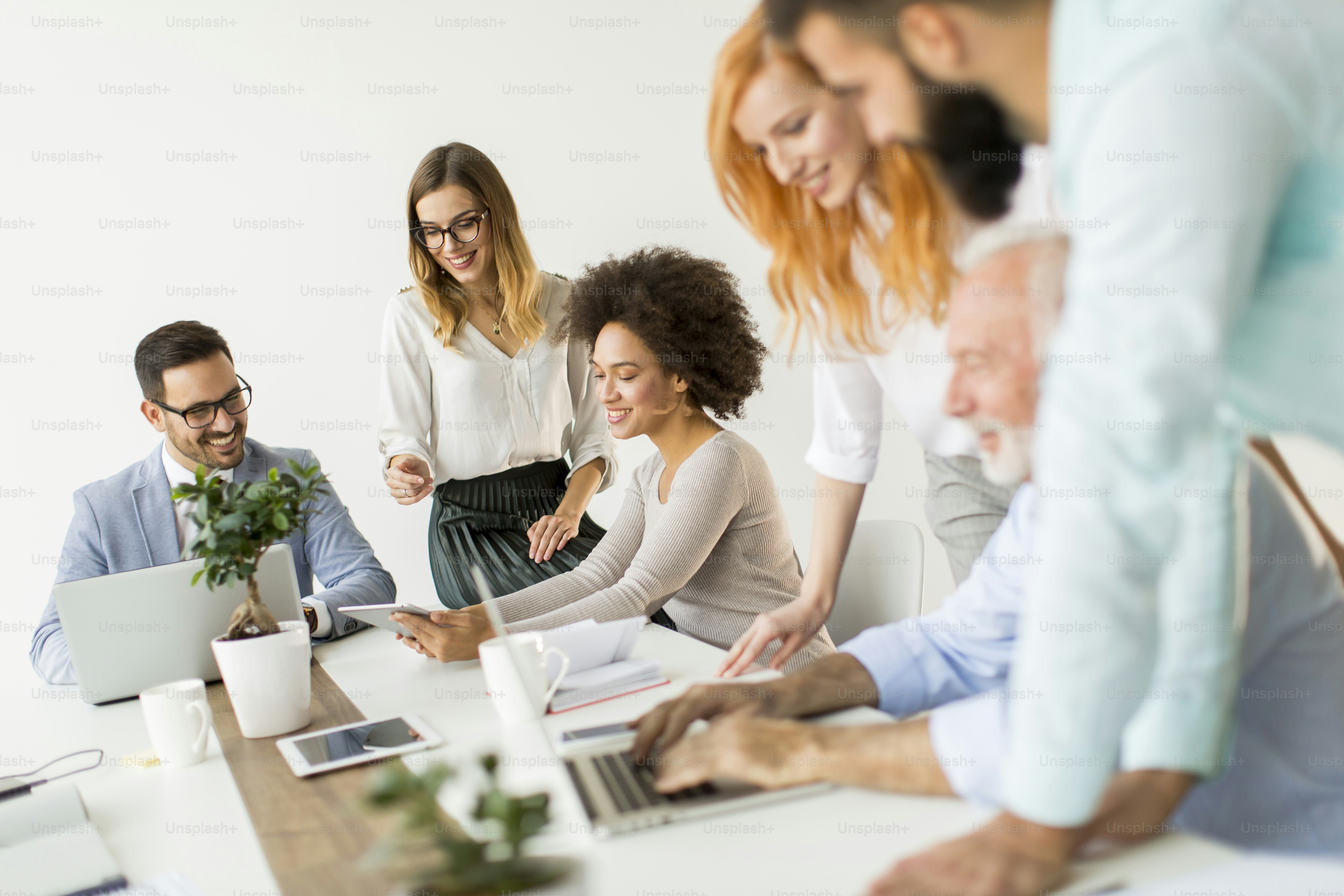 View at group of young multiracial business people around table during ...