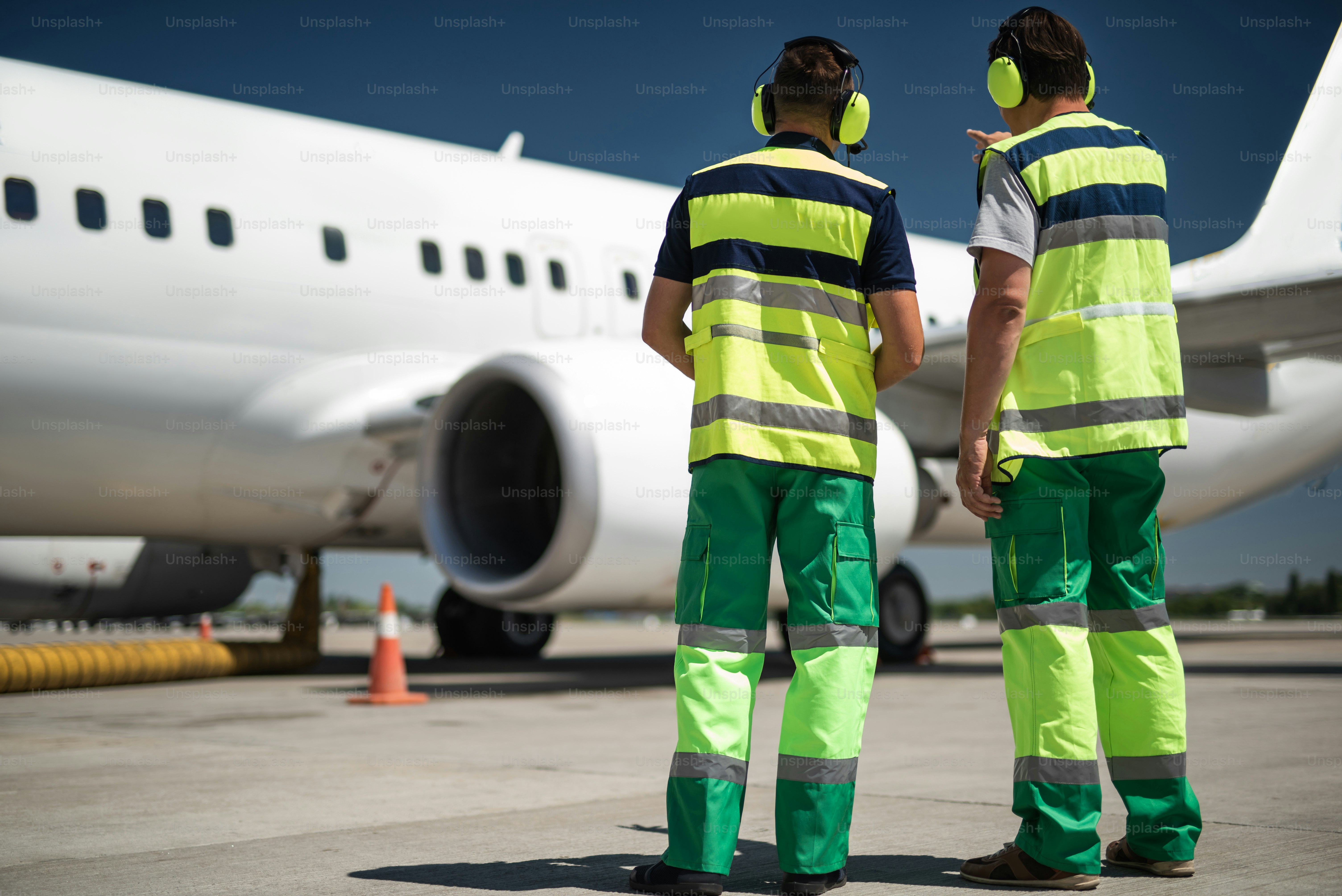 Let me show you. Back view of aviation personnel observing passenger ...