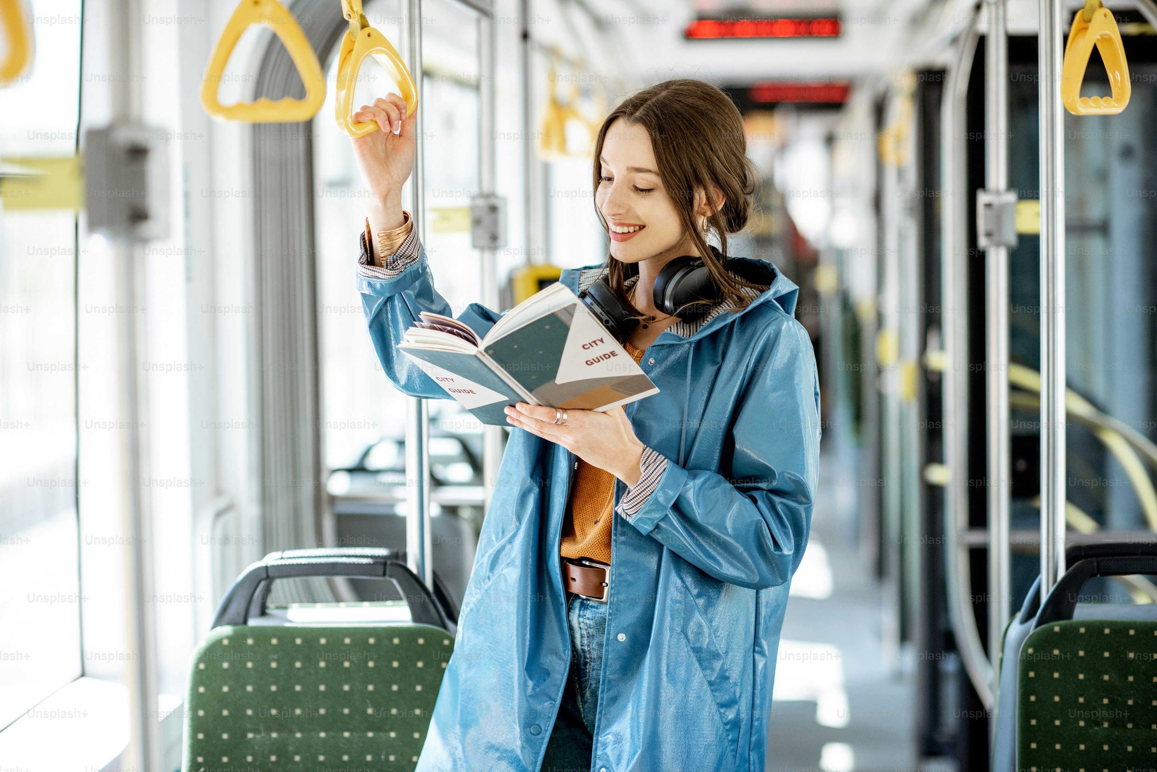 Young woman reading book while standing in the modern tram, happy ...
