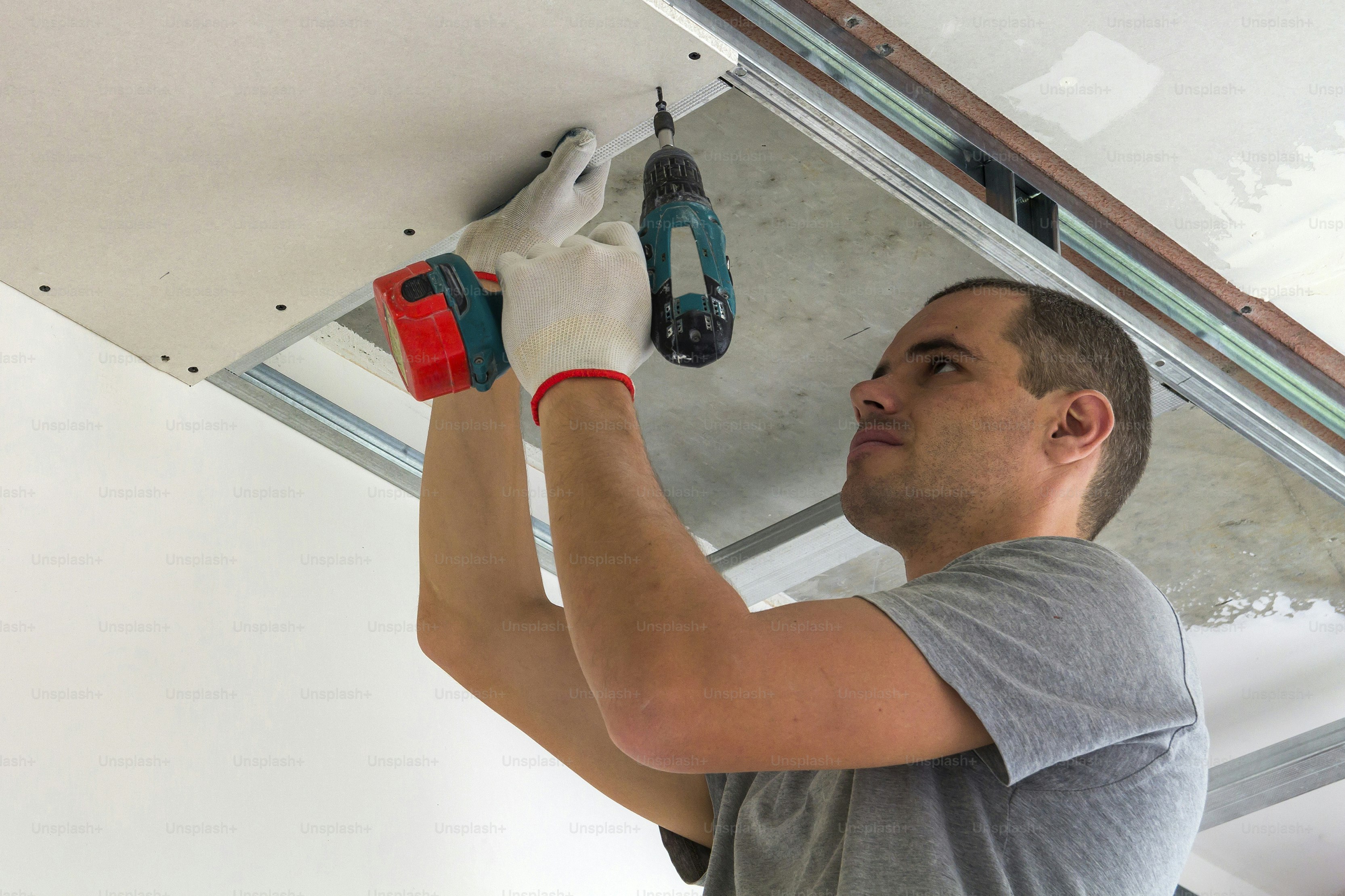 Construction worker assemble a suspended ceiling with drywall and ...