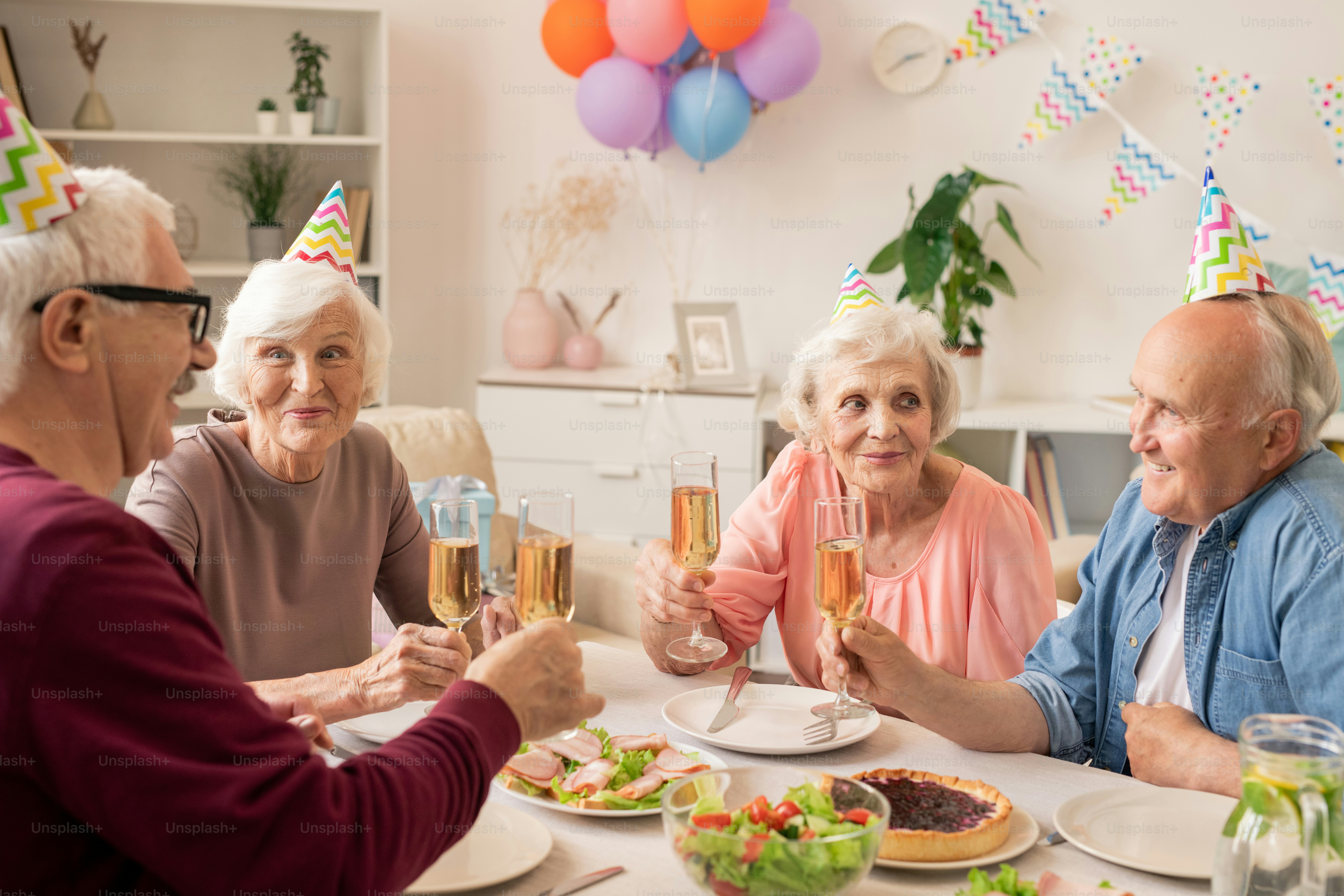 Group of senior people sitting by served table at home while ...
