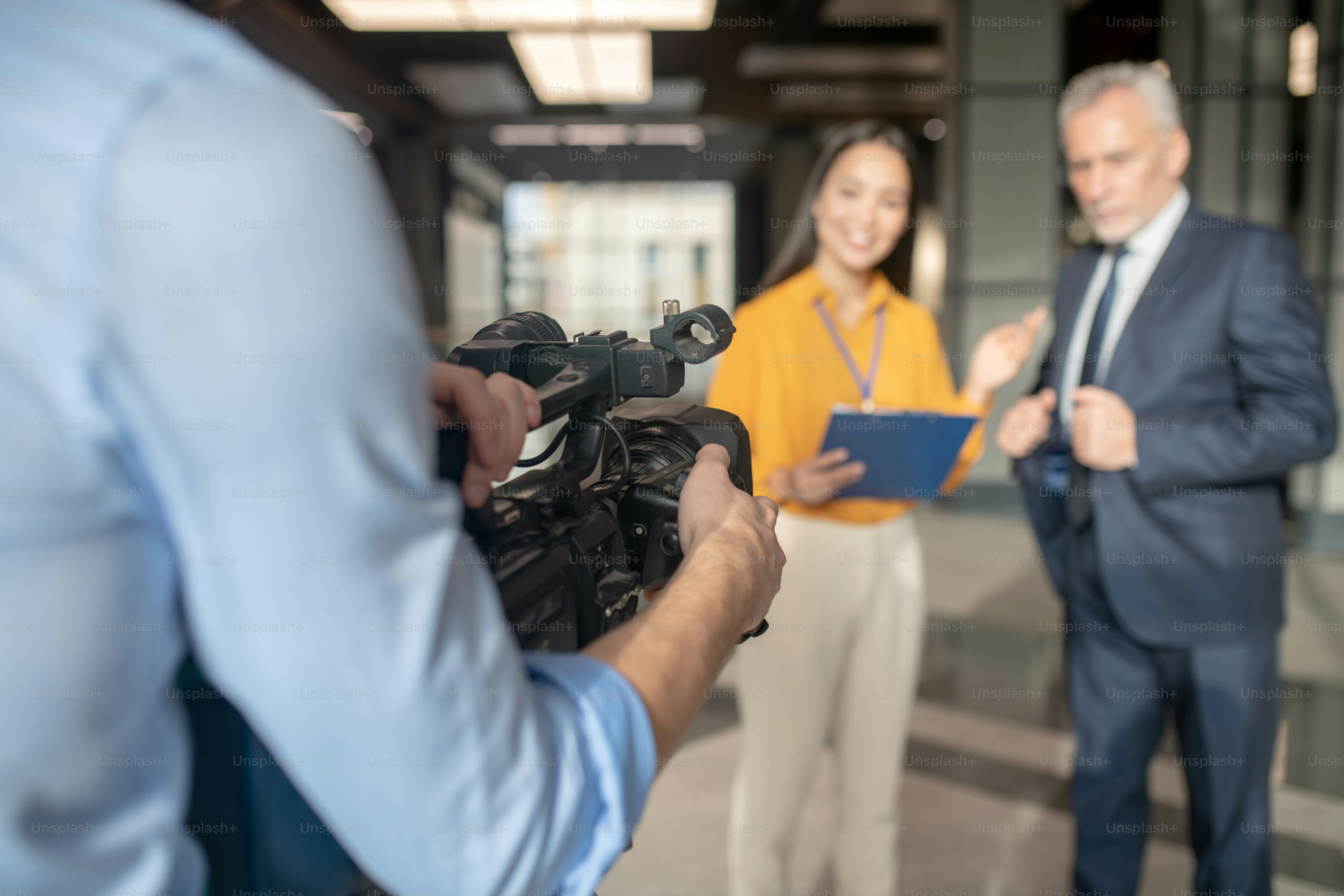 Feeling satisfied. Asian female reporter wearing beige pants smiling ...