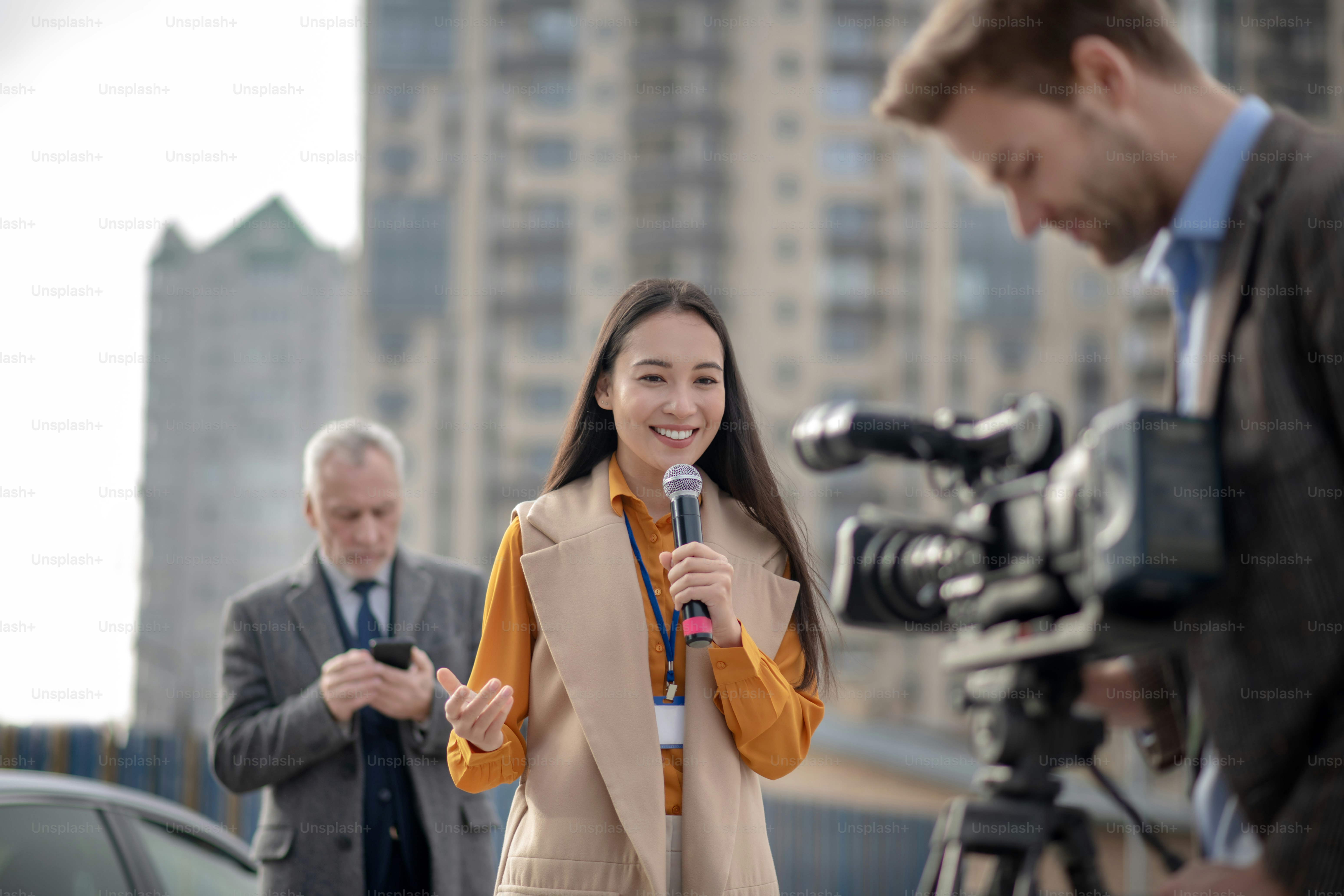 Live. Young cute female reporter in a beige outfit talking to a ...