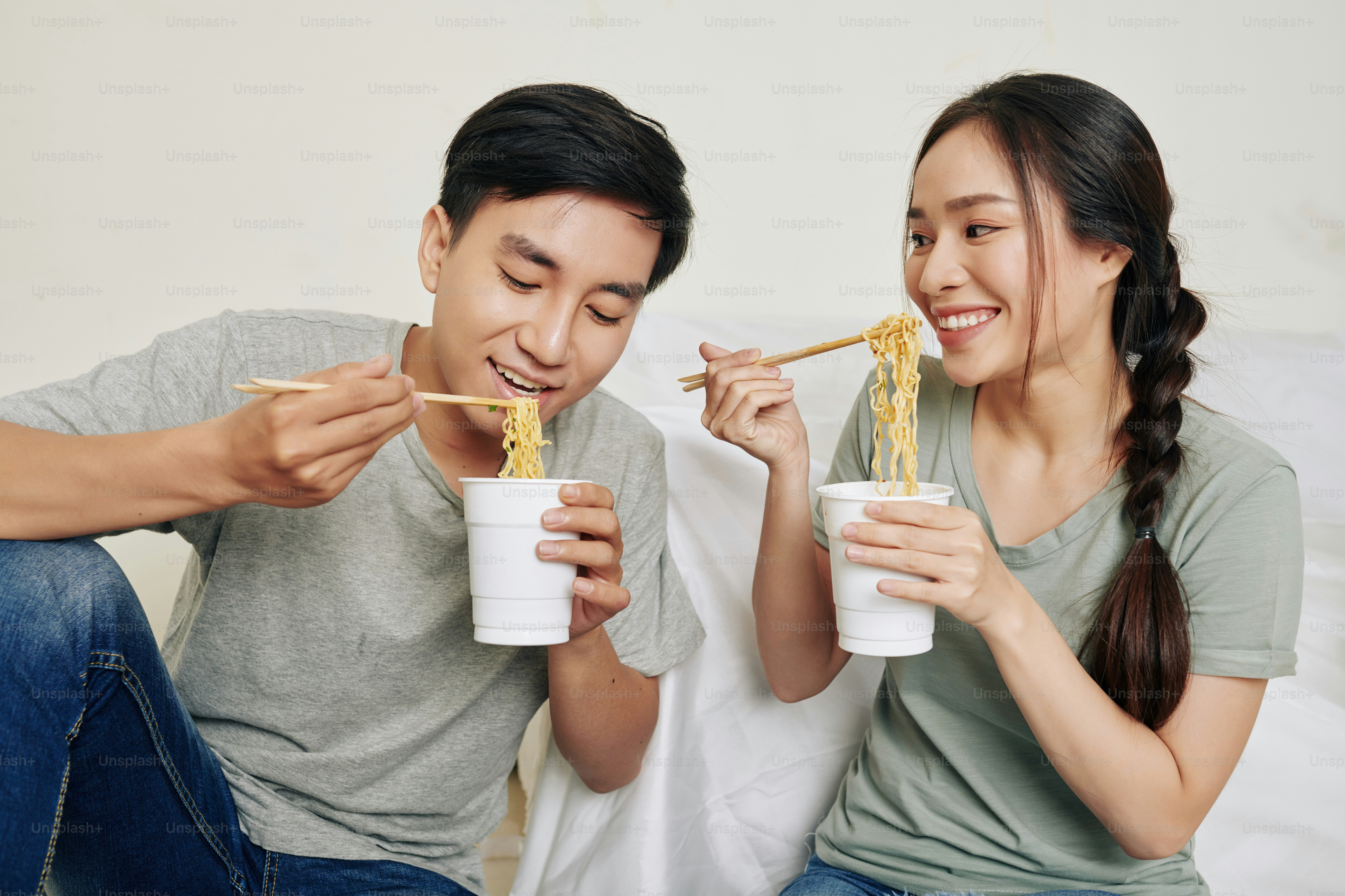 Happy young Vietnamese couple eating tasty ramen from plastic cups photo – Japanese food Image ...