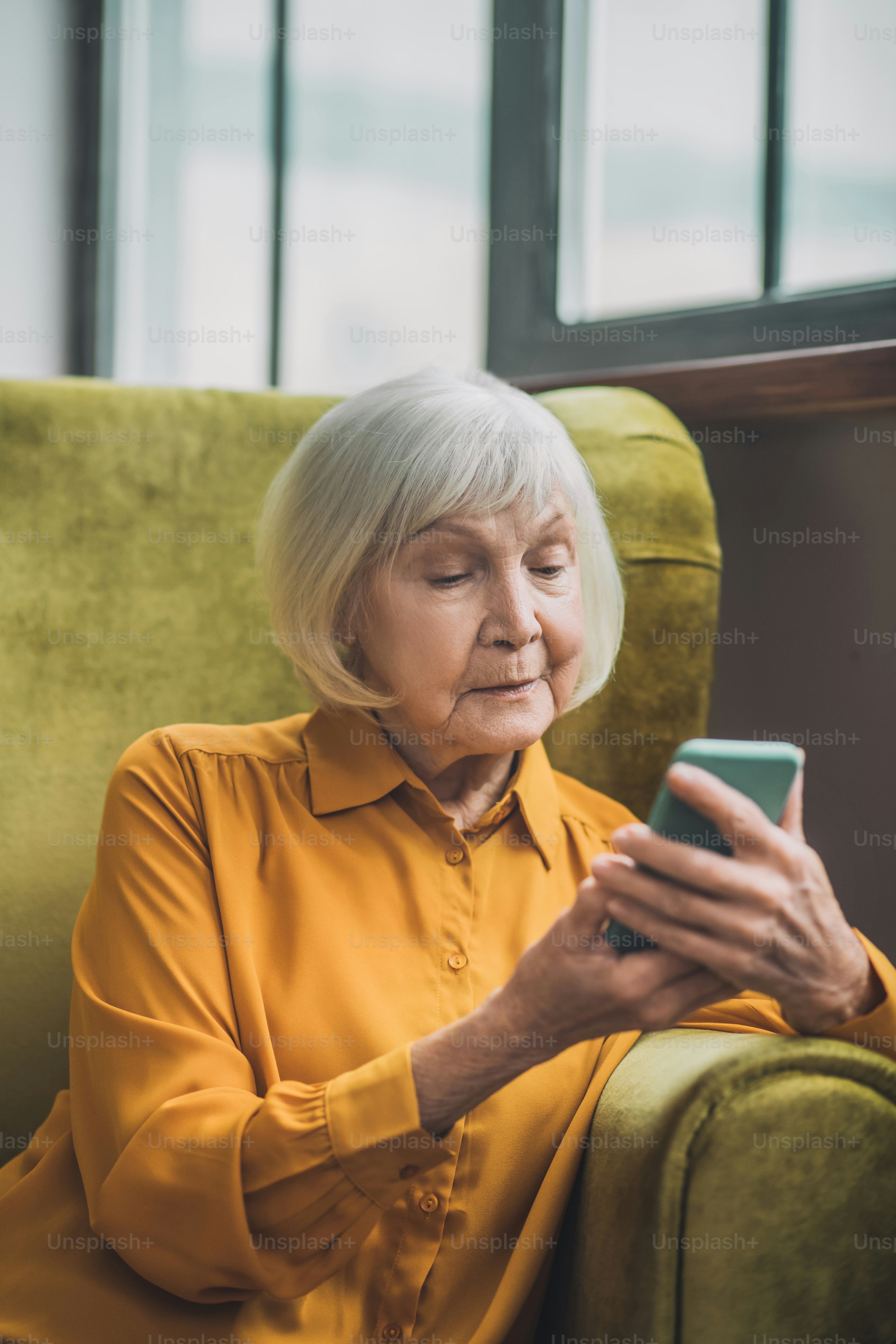 Online. Good-looking elderly lady in yellow typing a message photo ...
