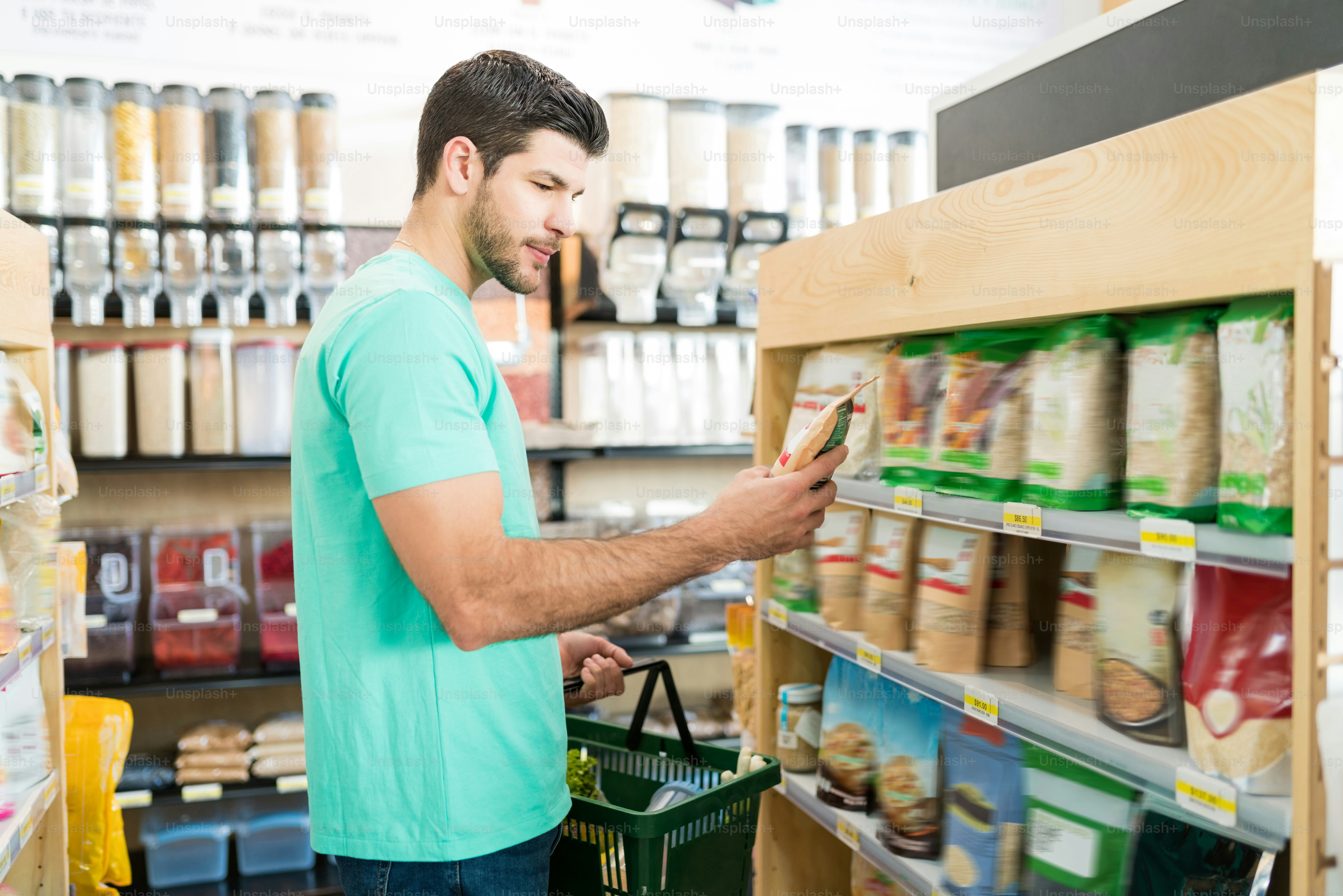 Side view of handsome Latin man buying food product in supermarket ...