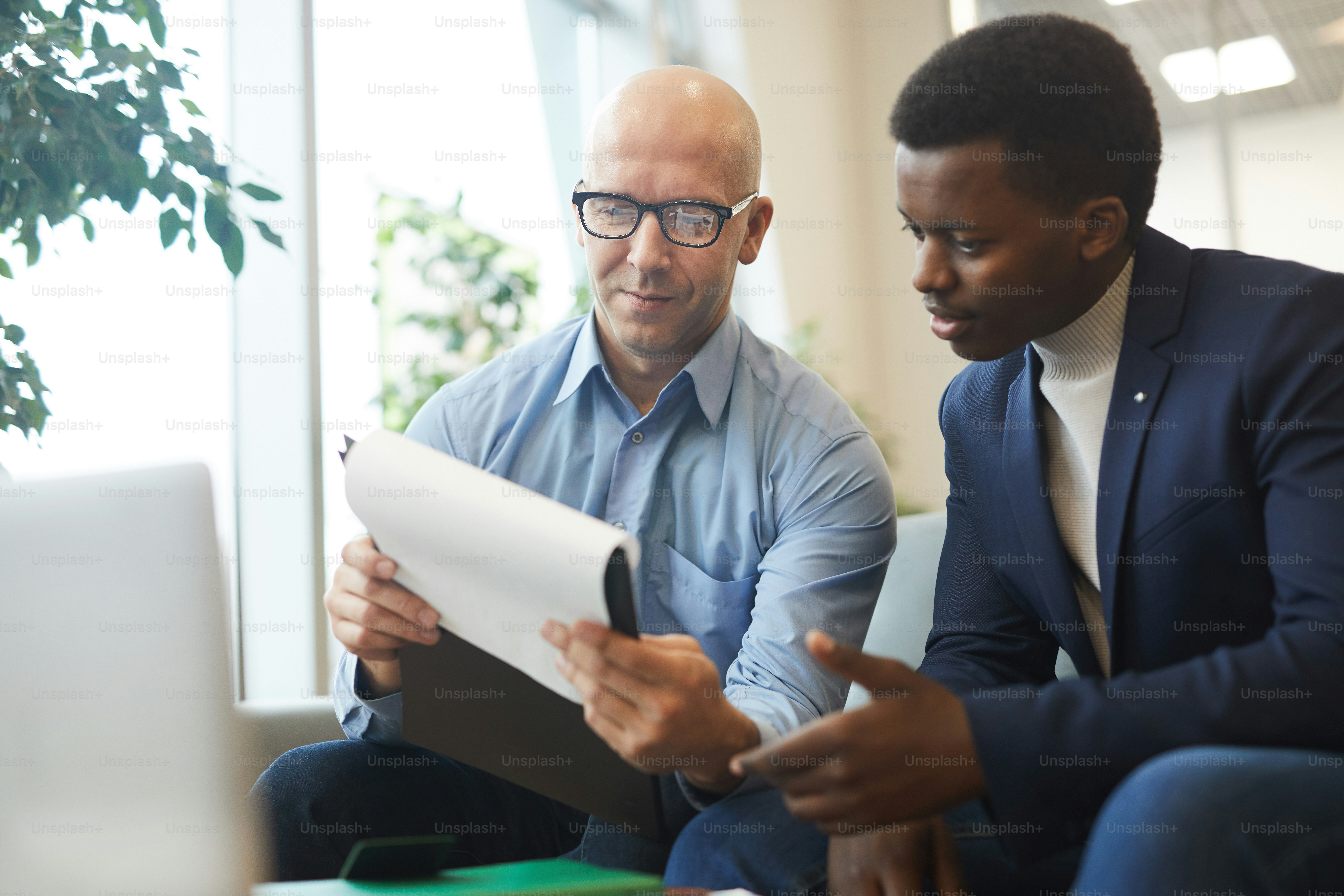 Portrait of young African businessman talking to manager while working ...