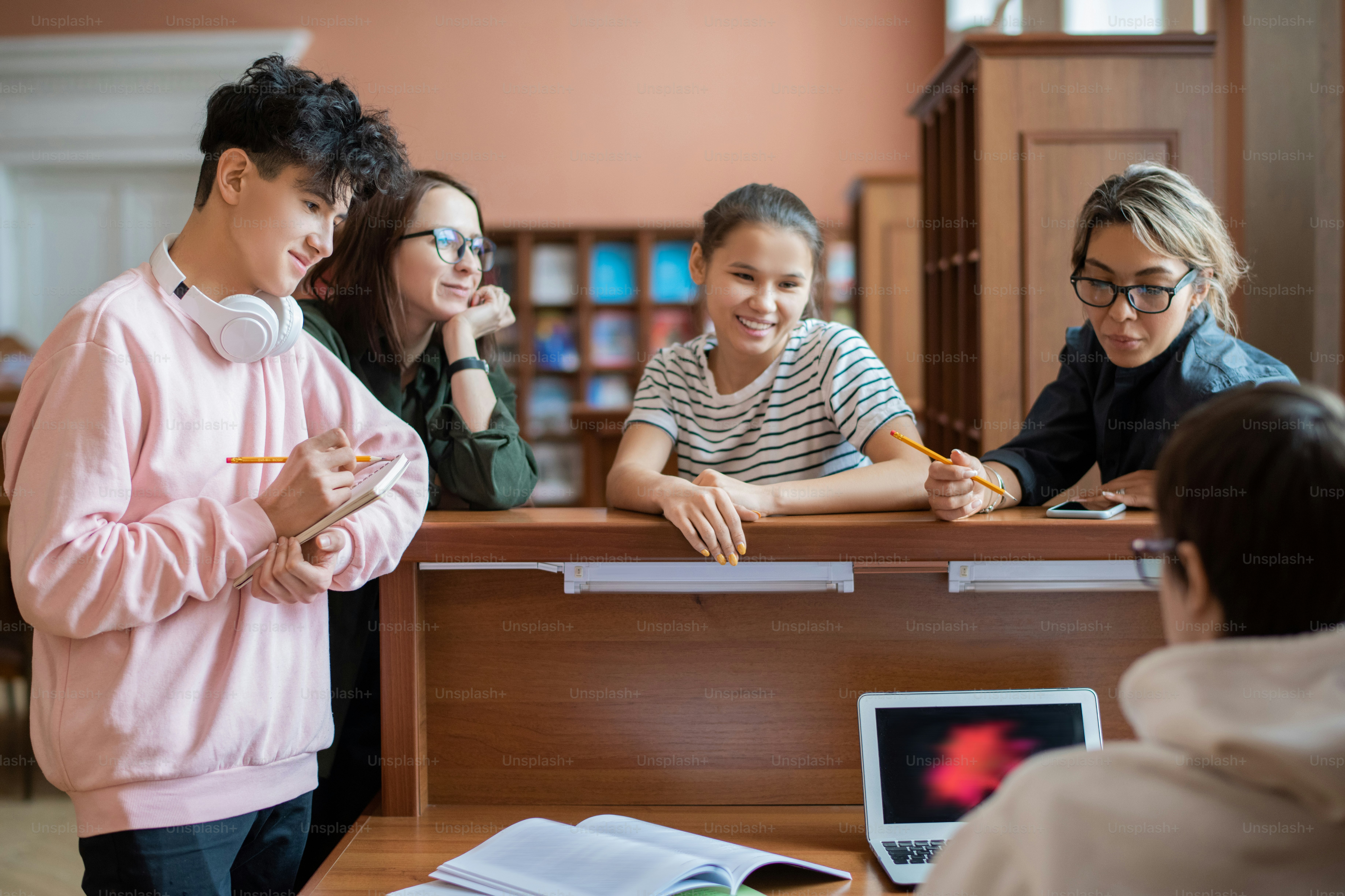 Group of clever college student standing by programmer in front of ...