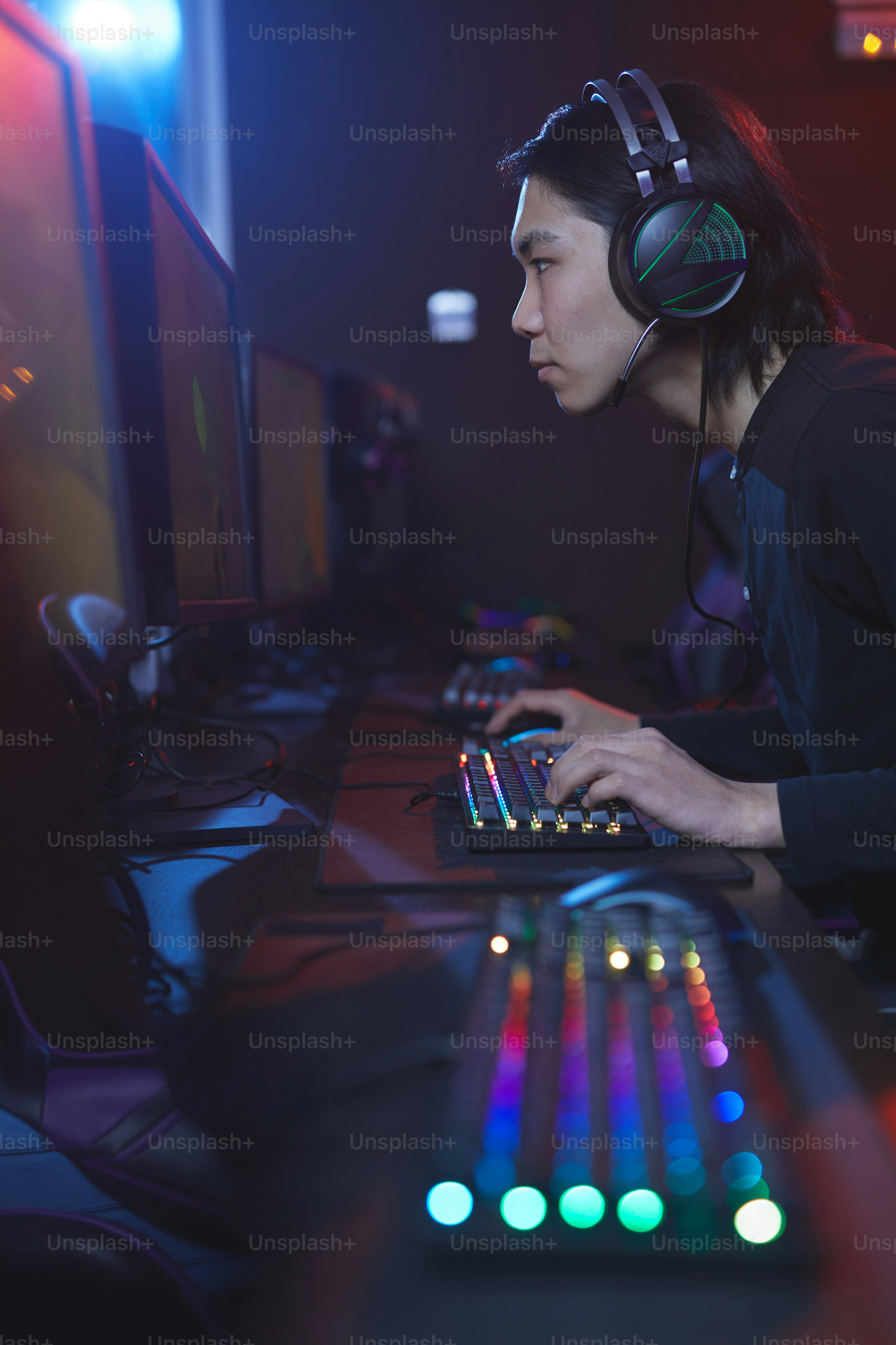 Vertical side view portrait of young Asian man using computer in cyber ...