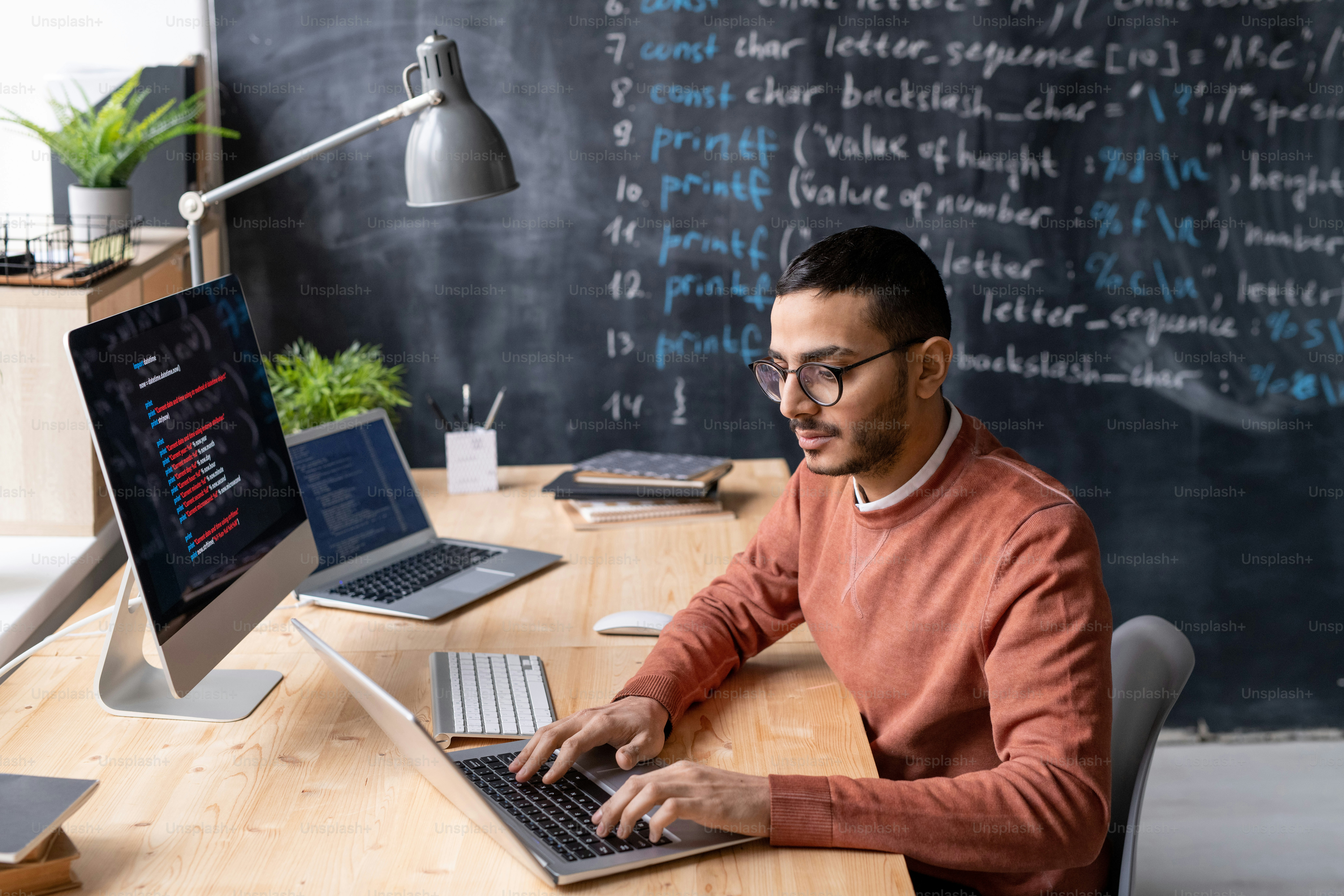 Contemporary it-manager in eyeglasses sitting by table in front of ...