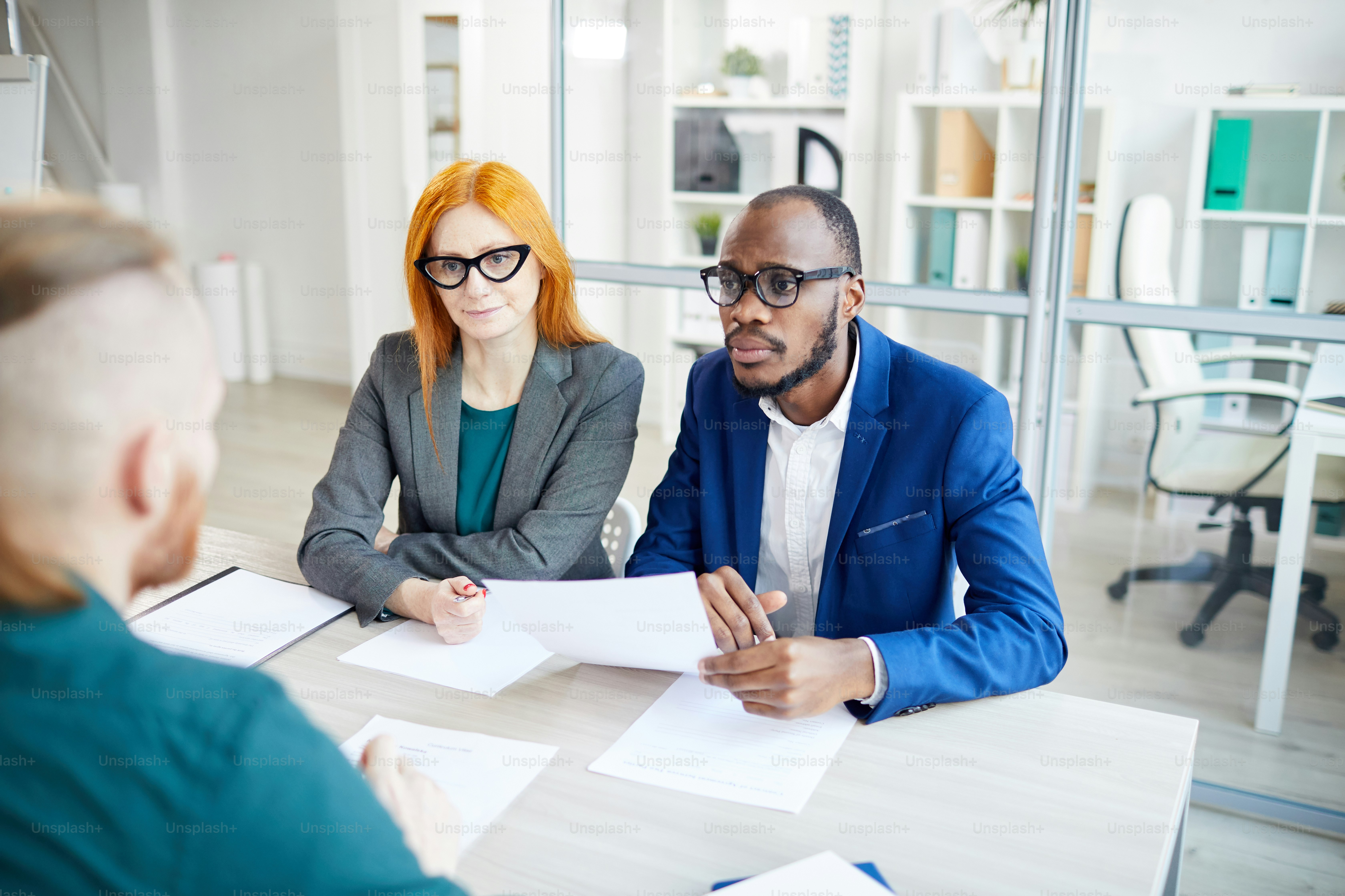 High angle view at two HR managers listening to candidate during job ...