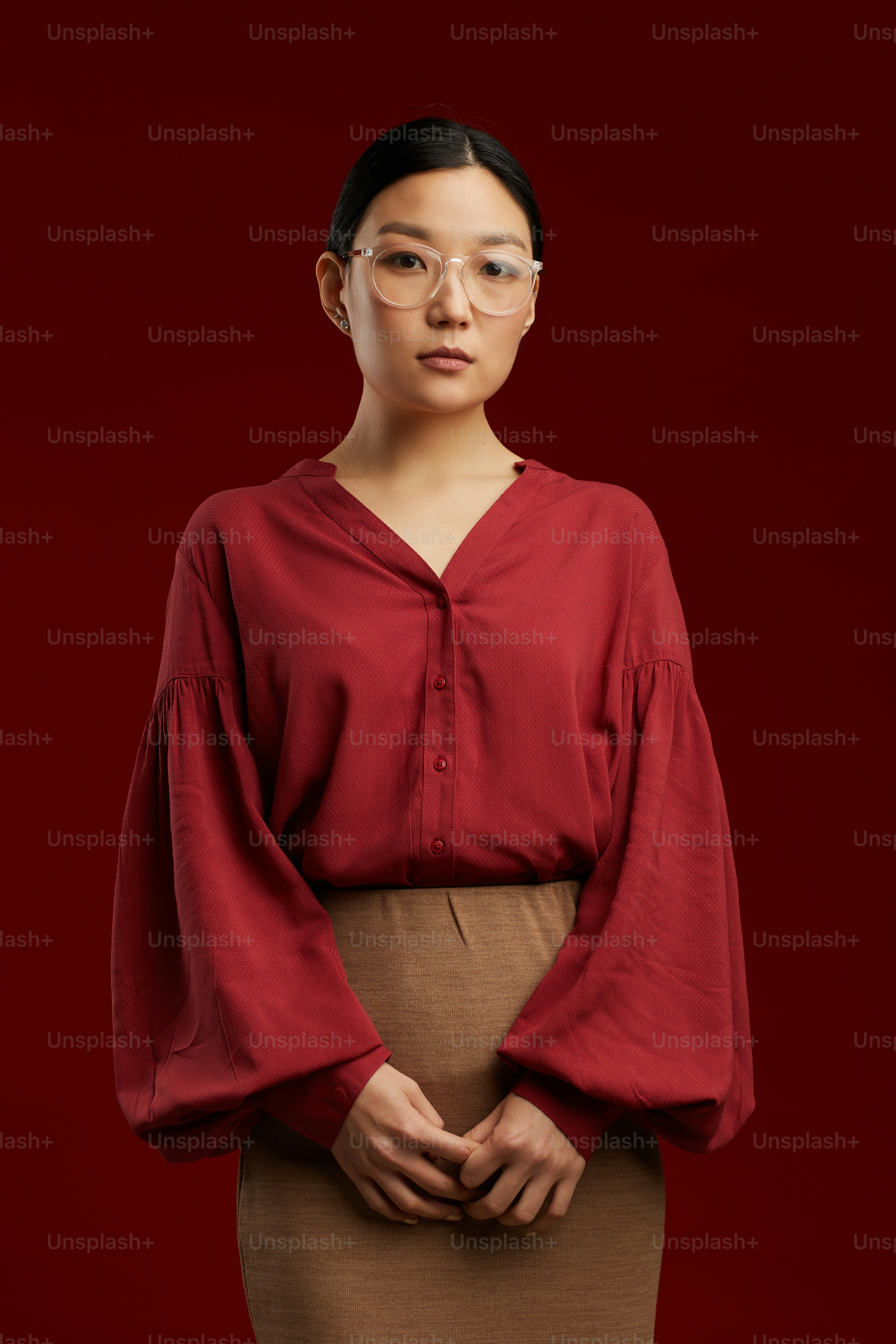 Professional portrait of elegant Asian woman standing by maroon ...